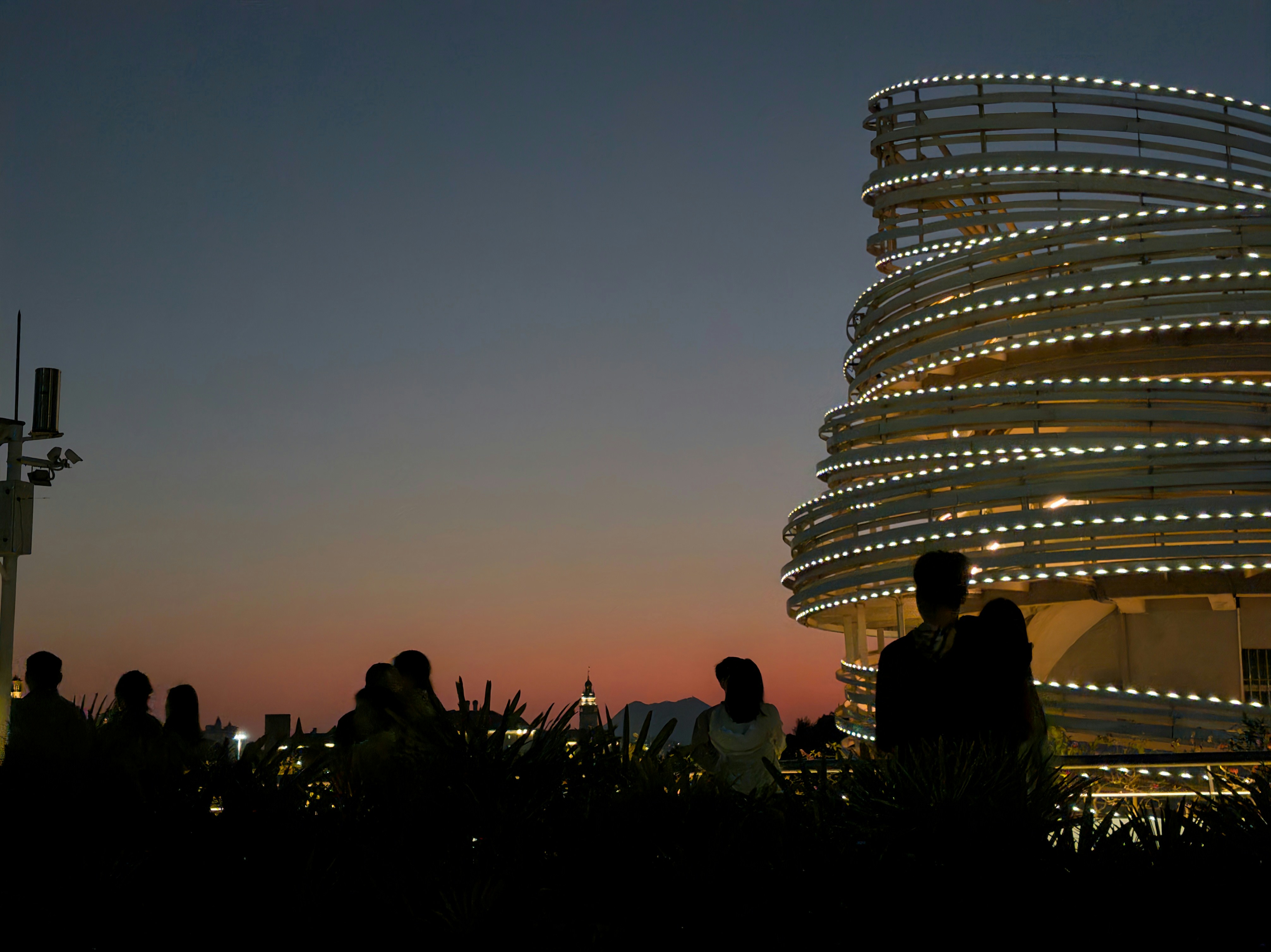Rooftop Evening: Silhouettes Against a Luminous Spiral