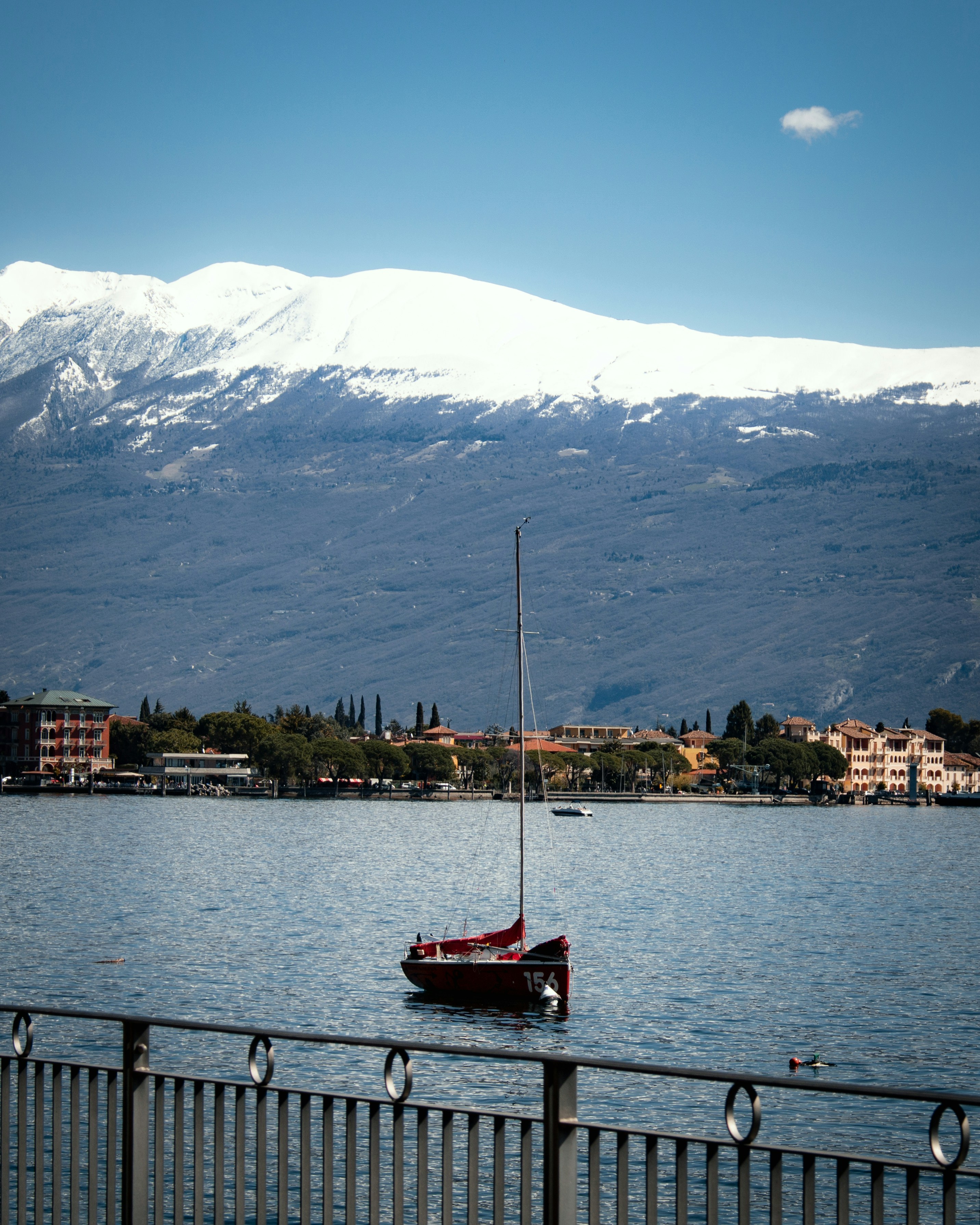 Azure Lake, Snow-Capped Backdrop, and a Red Sloop at Dusk