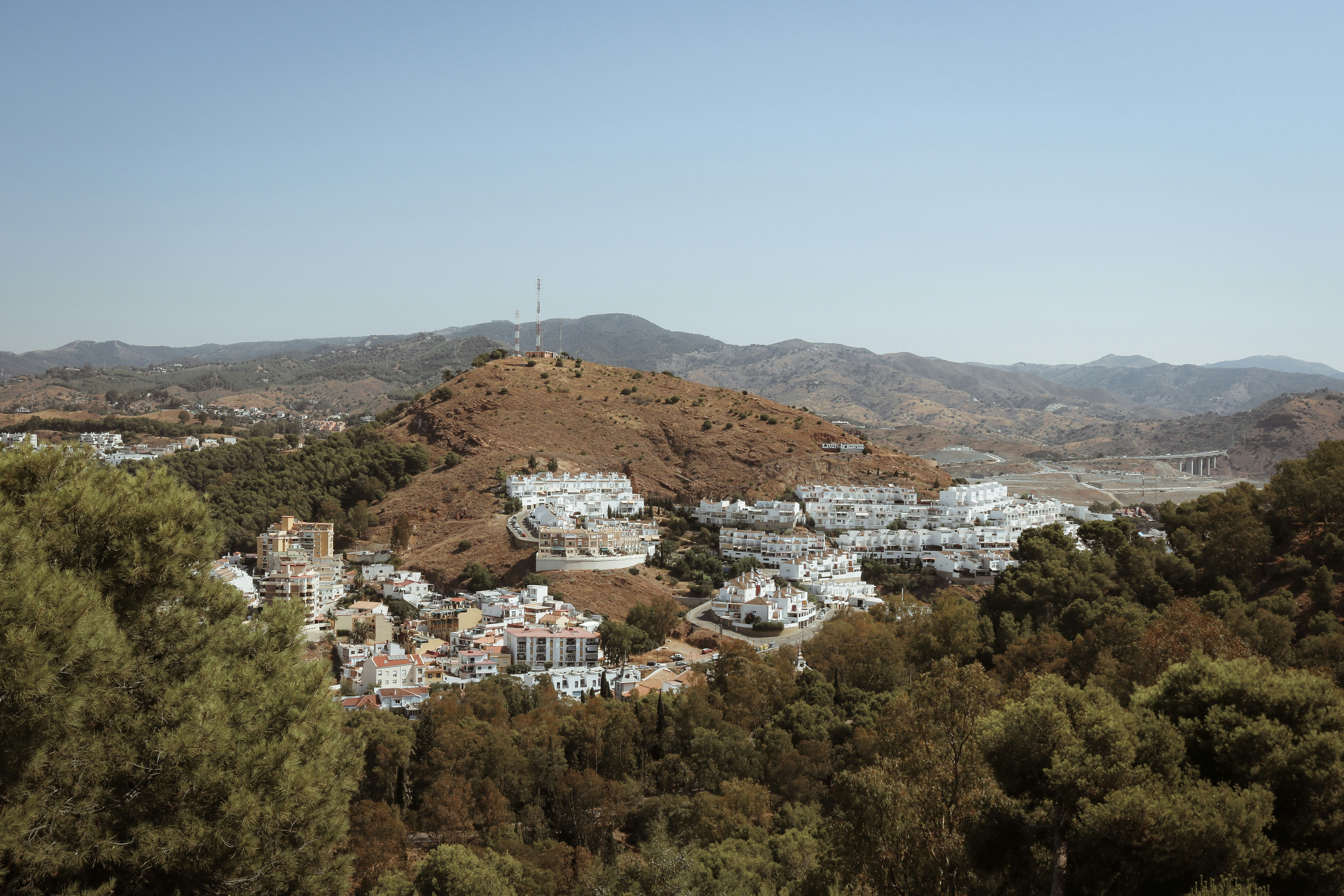 Terraced village on sunlit hills beneath a calm blue sky