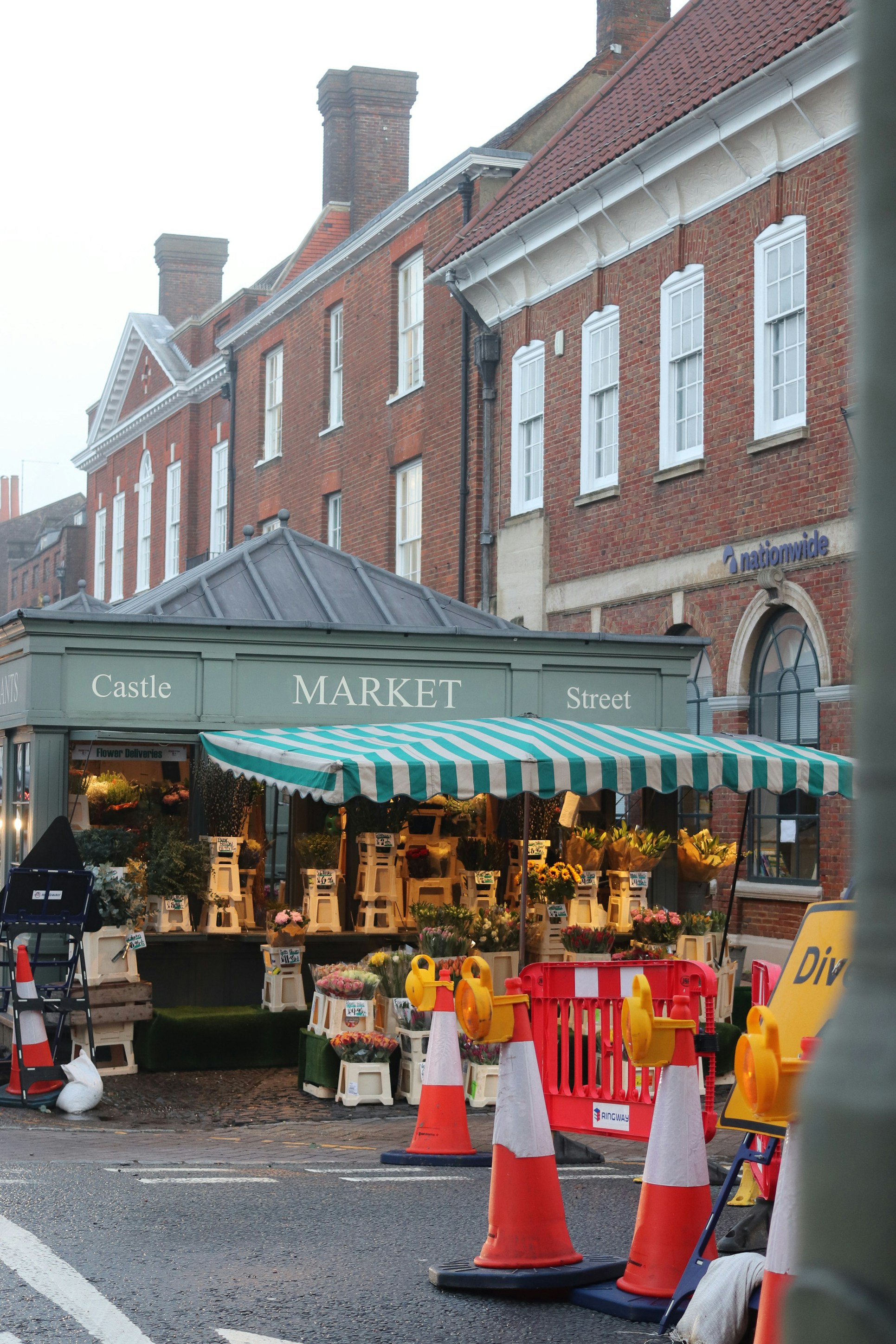 Green-and-white Market Canopy Framing a Brick Street Market Scene