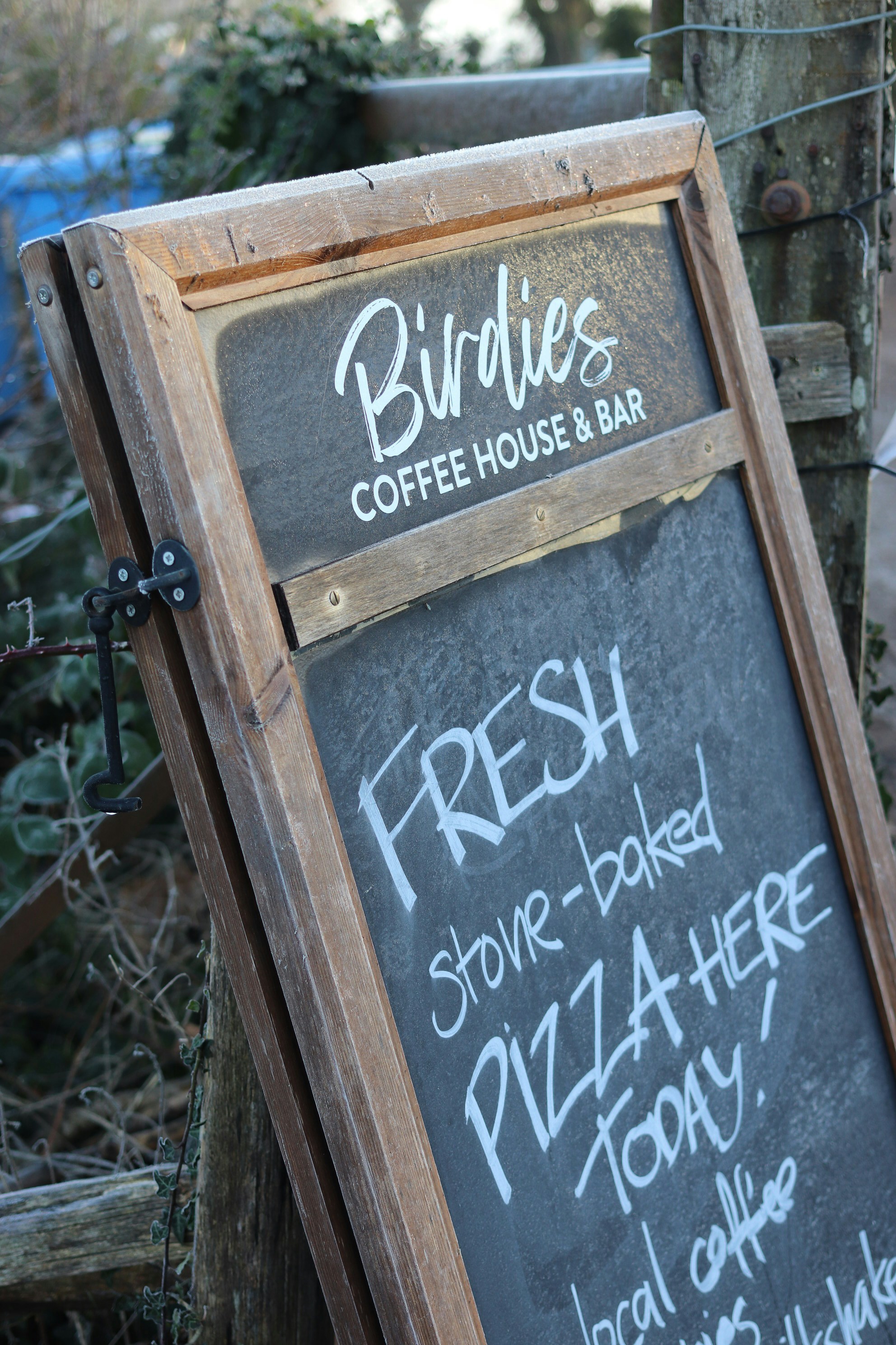 Chalkboard Café Sign Leaning Against a Fence
