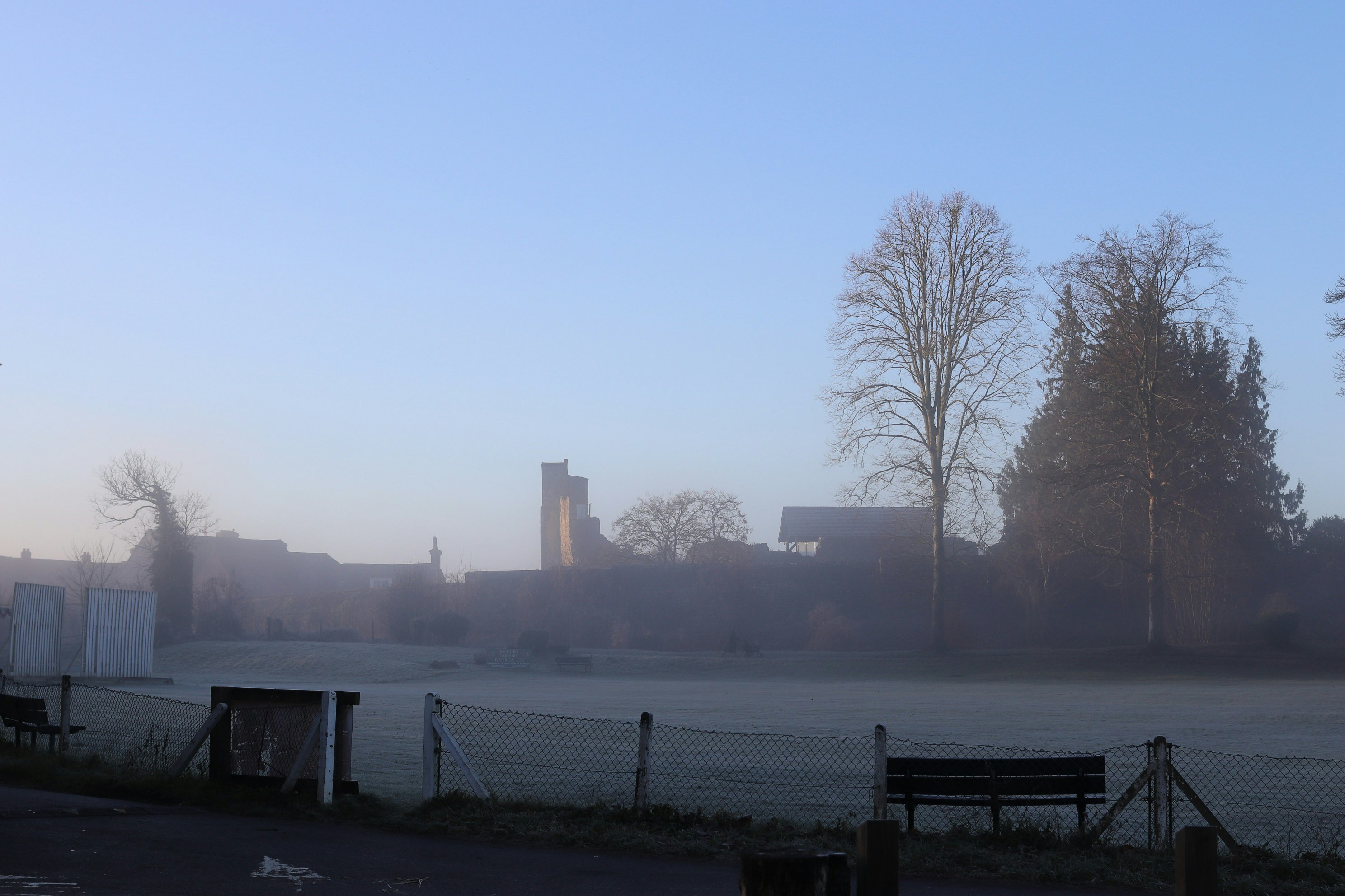 Misty Common View: A Quiet Riverside with Distant Silhouettes