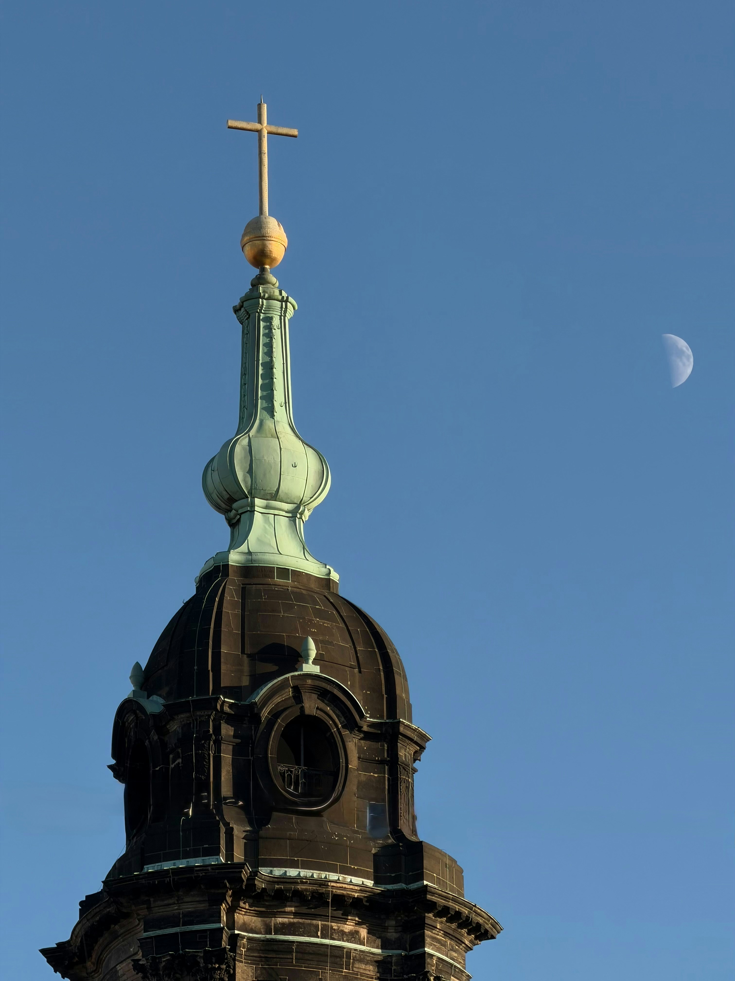 Spire Against a Clear Blue Sky with a Crescent Moon