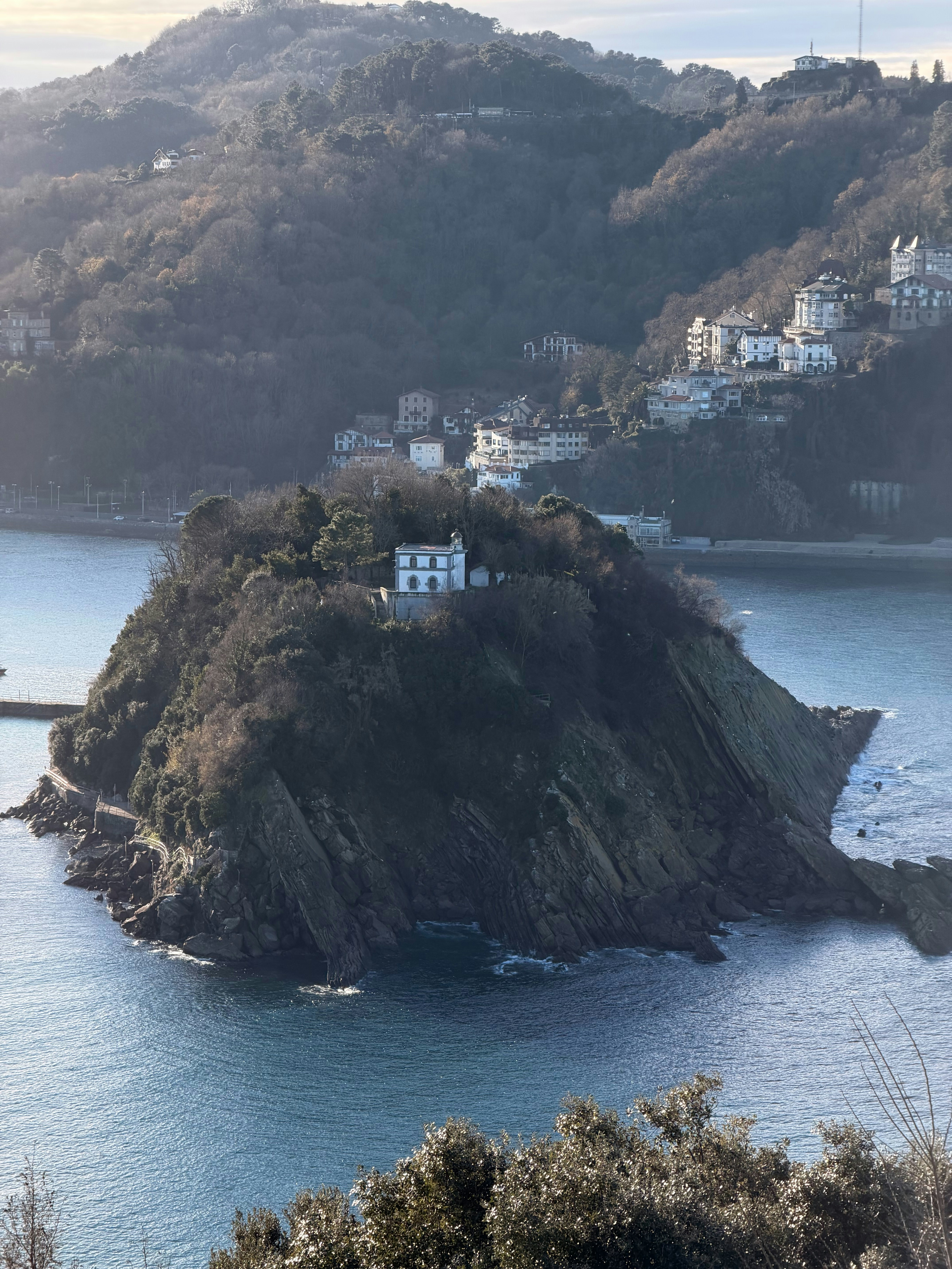 Islanded white house perched on a rocky promontory above a calm coastal inlet