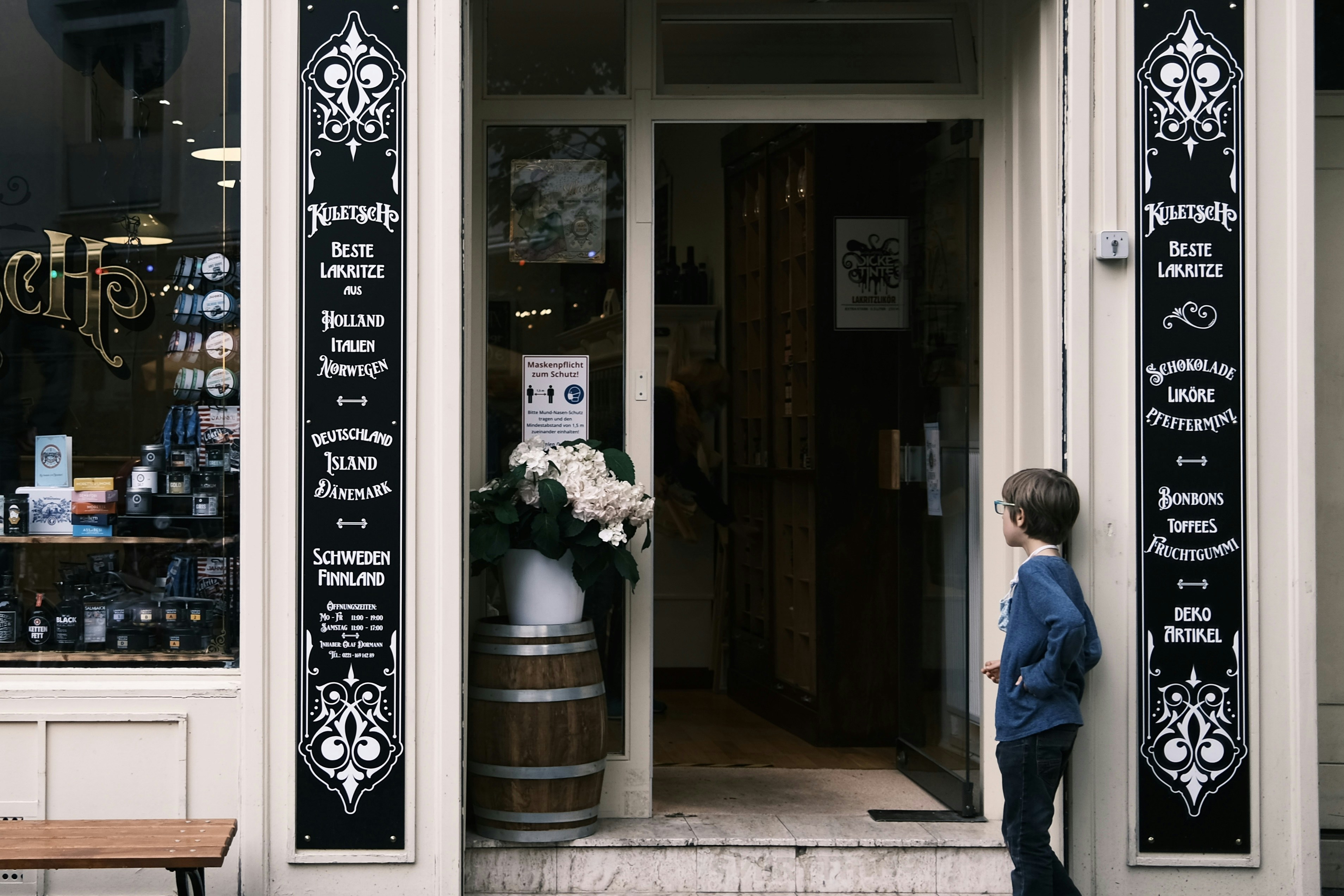 A Quiet Doorway: A Boy in Blue Contemplates an Open Shop