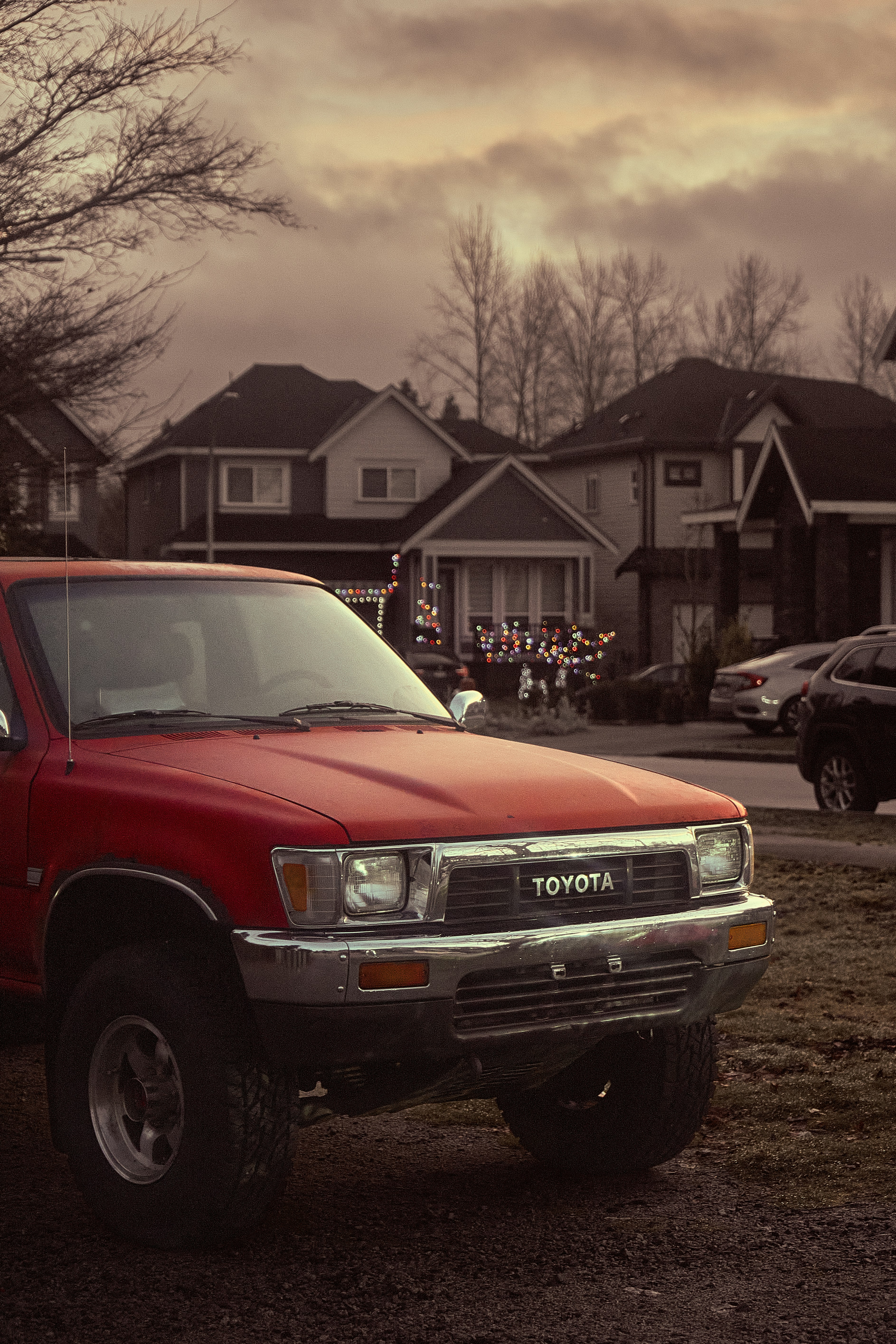 Red Toyota Pickup with Festive Glow in Suburban Driveway