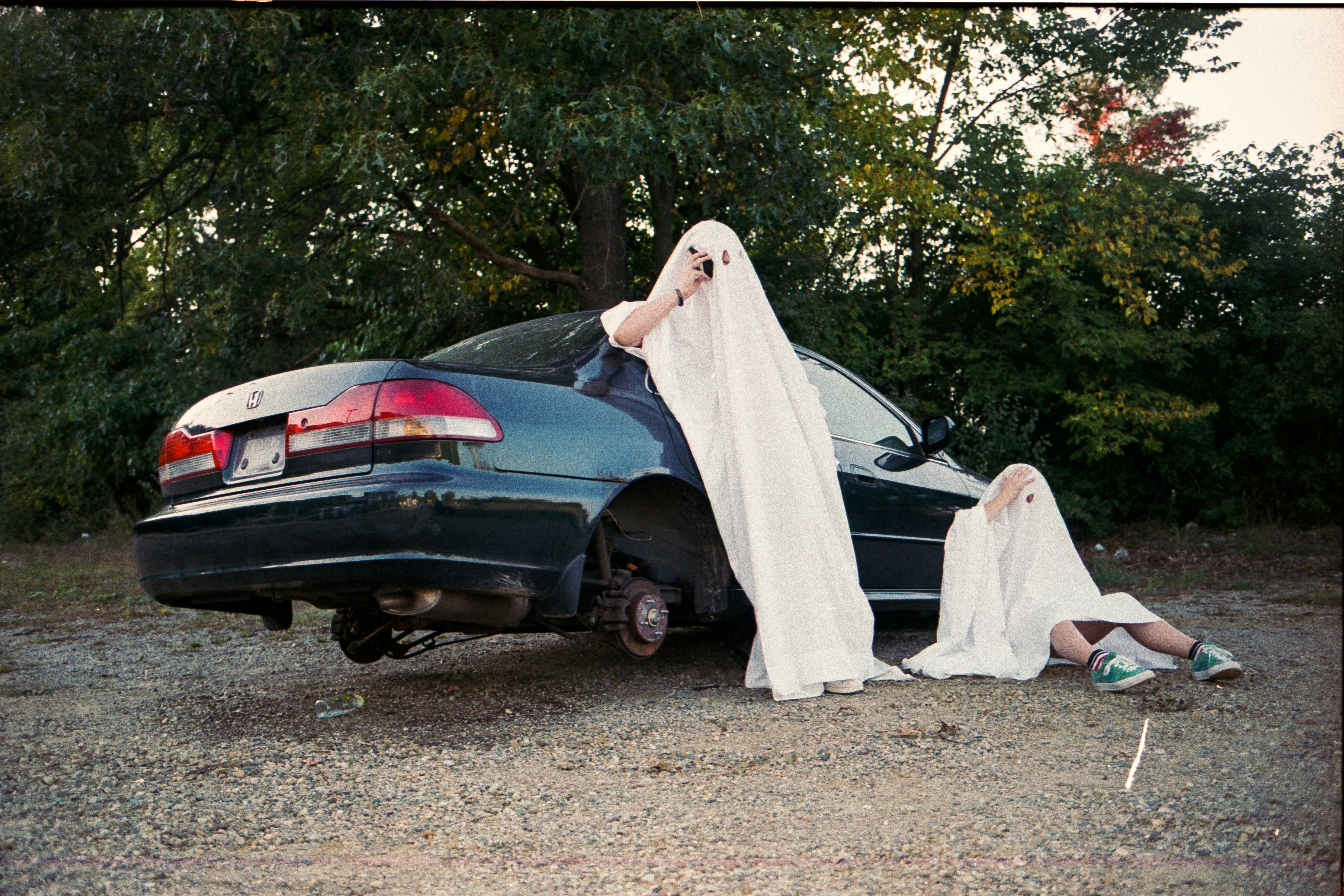 Two people in sheets near a car