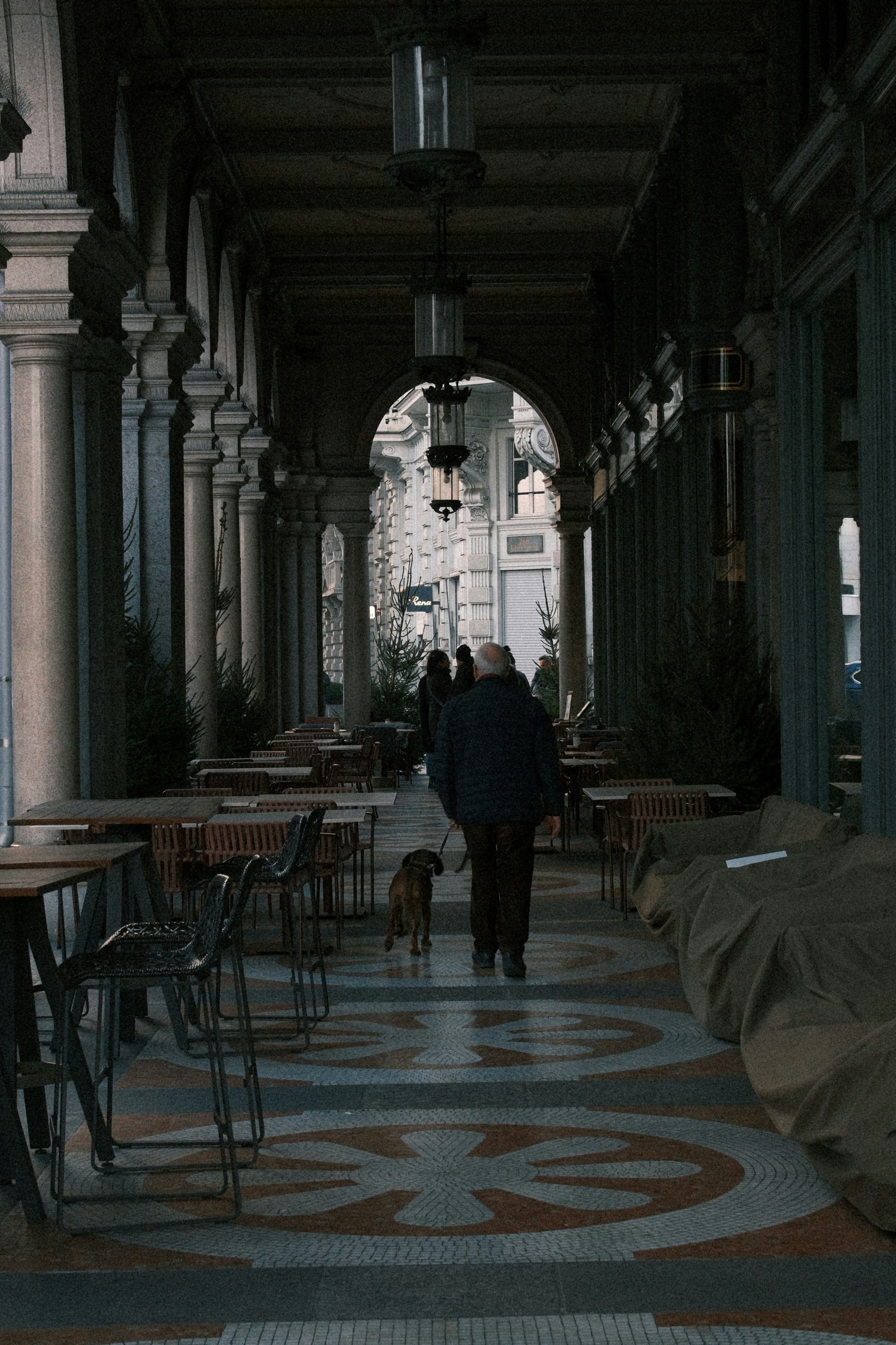 Quiet Archway Walk: A Couple and Their Dog in a Cloistered Arcade