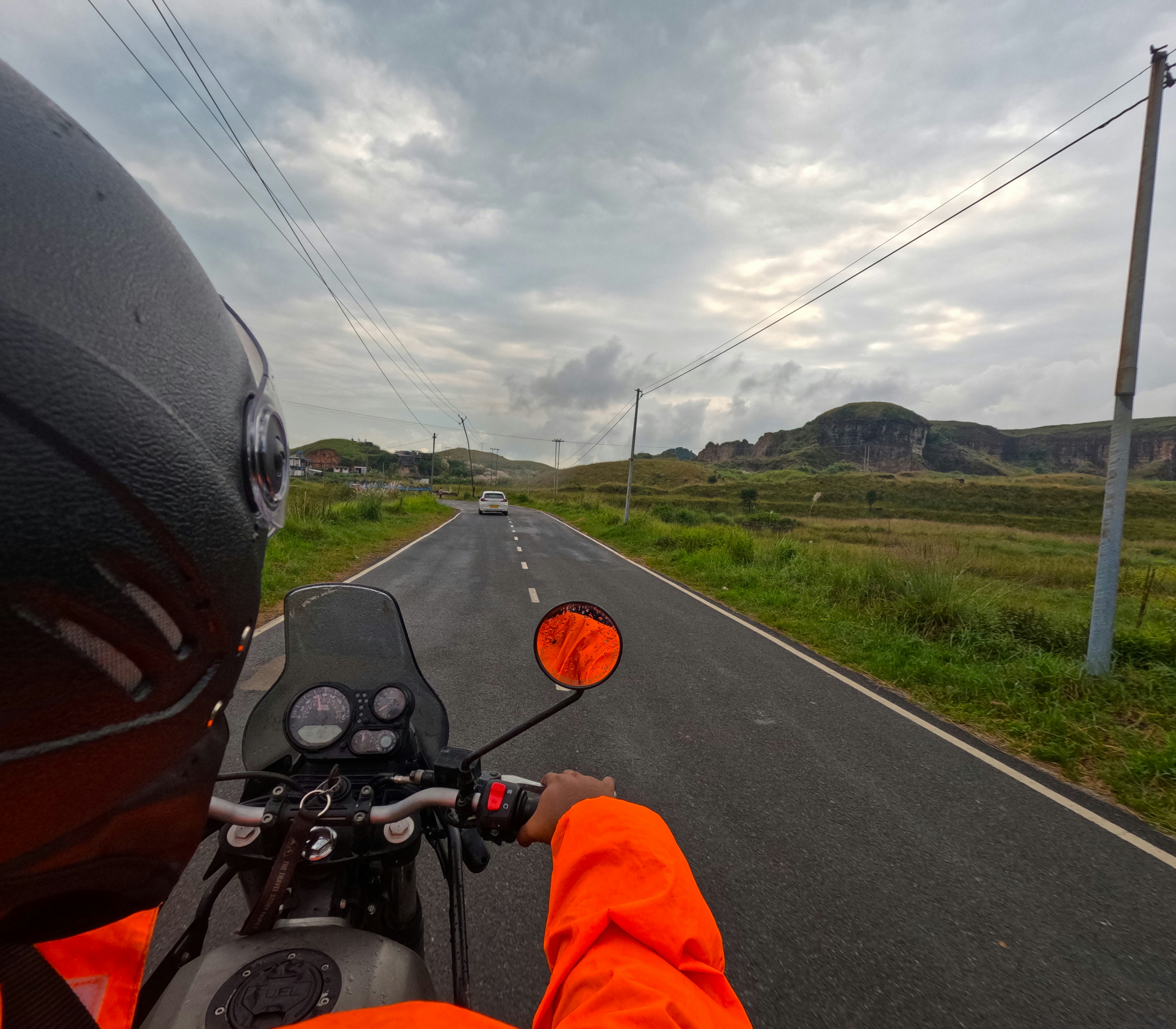 Riding a motorcycle on a road with cloudy sky.