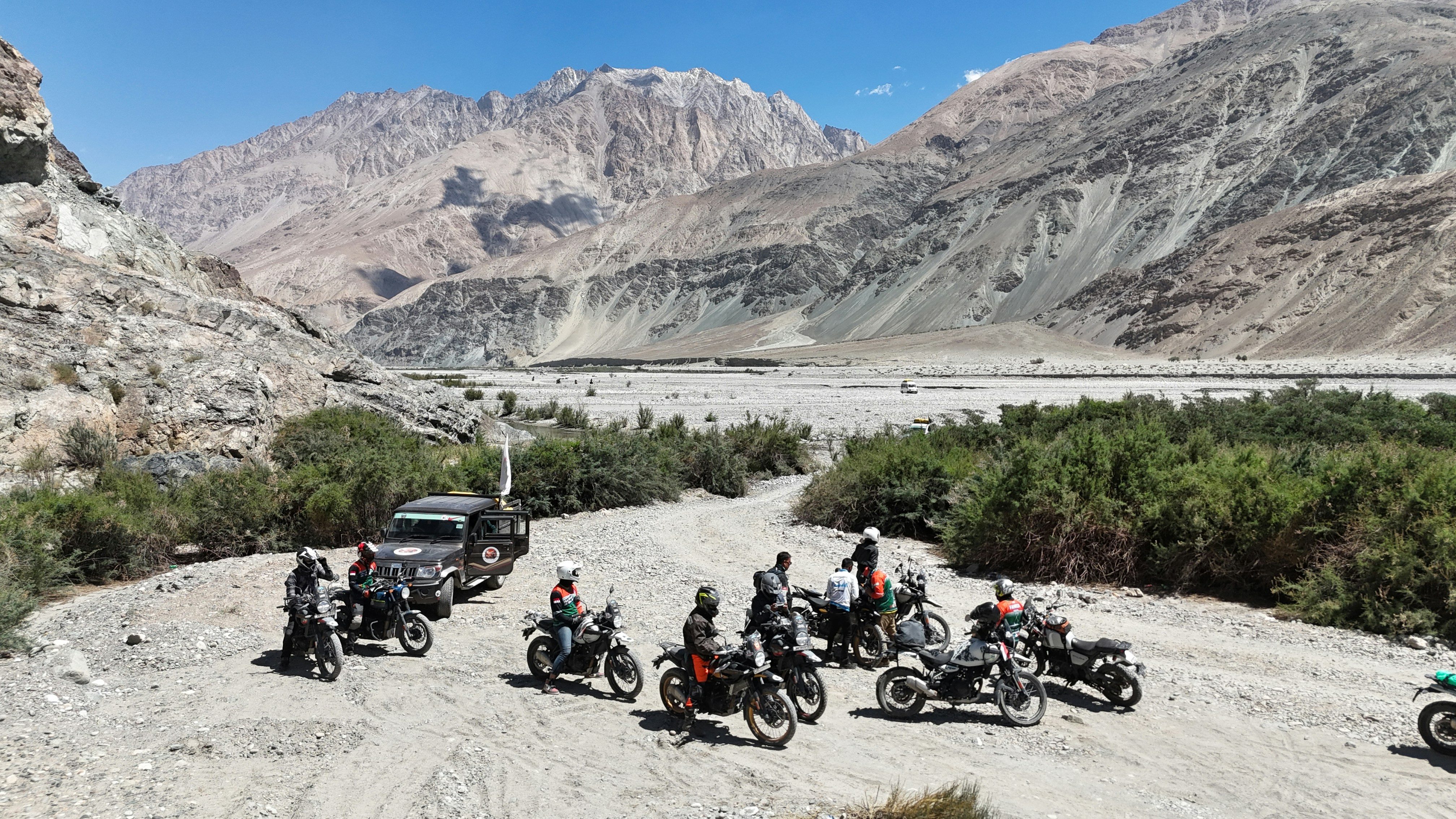 Ridge-Top Rally: a convoy of off-roaders rests with rugged peaks in the background