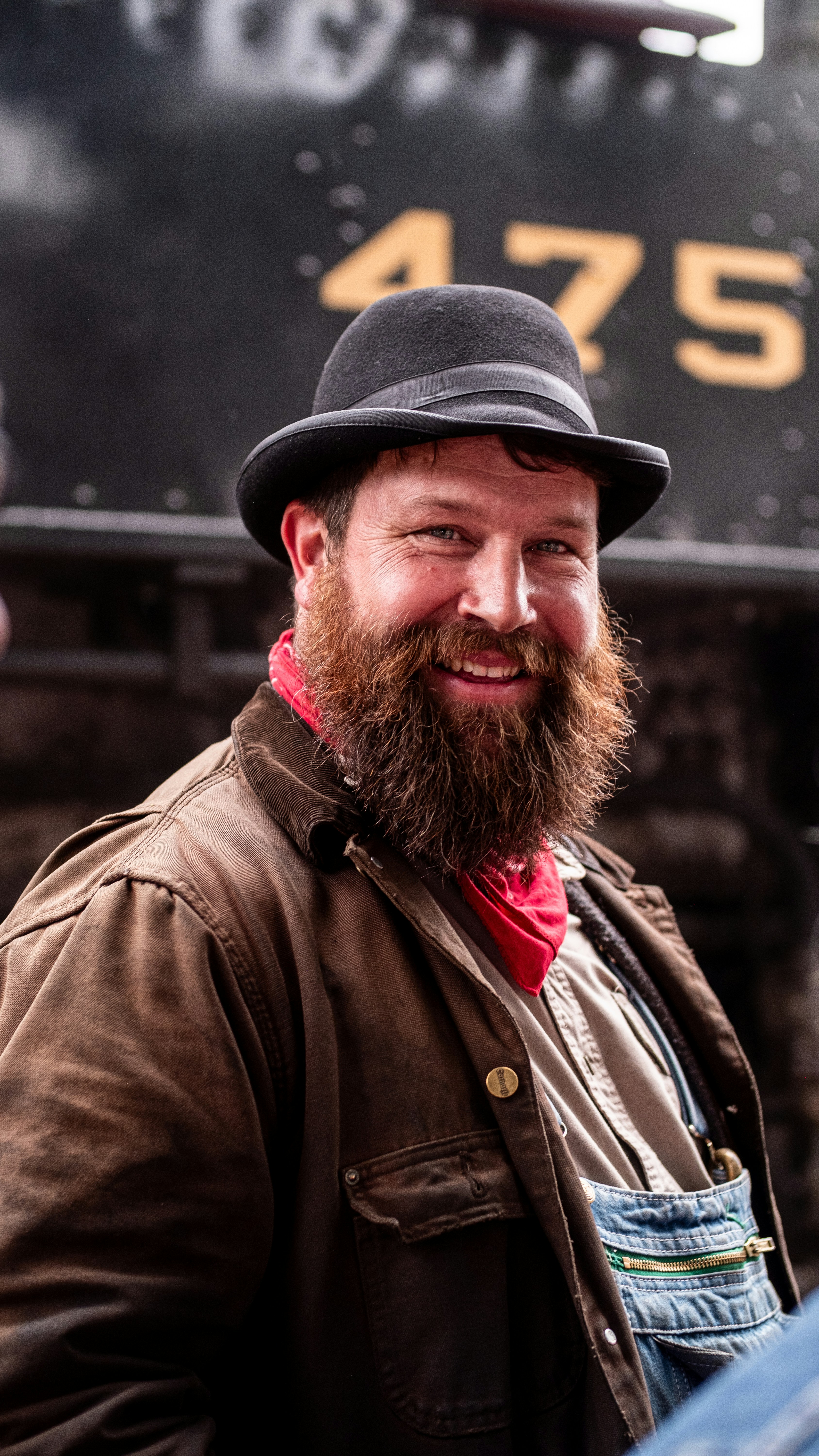 Smiling Railworker in Warm Attire Beneath a Black Engine