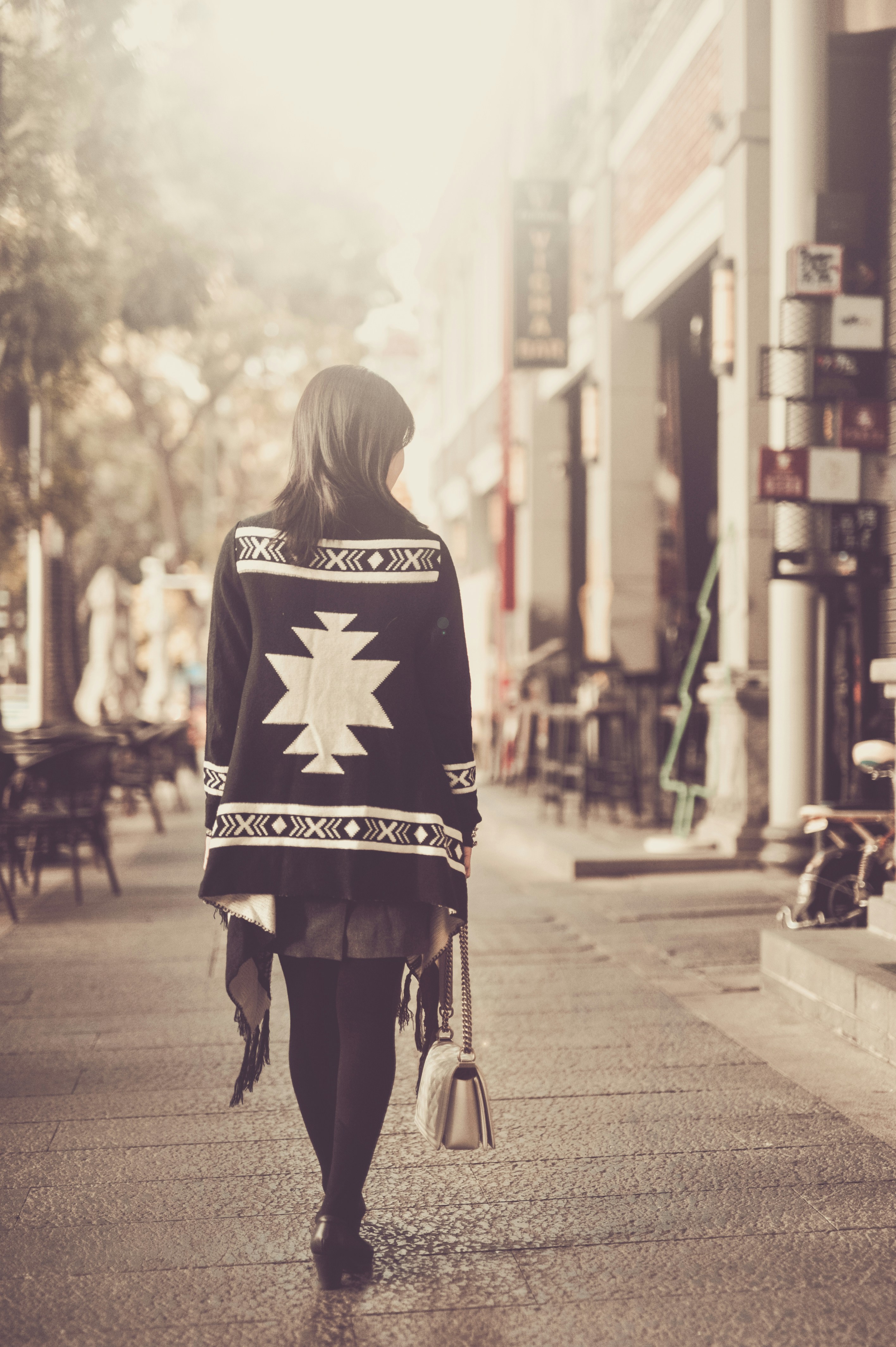 Shadowed Walk: A Woman in a Geometric Poncho Steps into the City Light