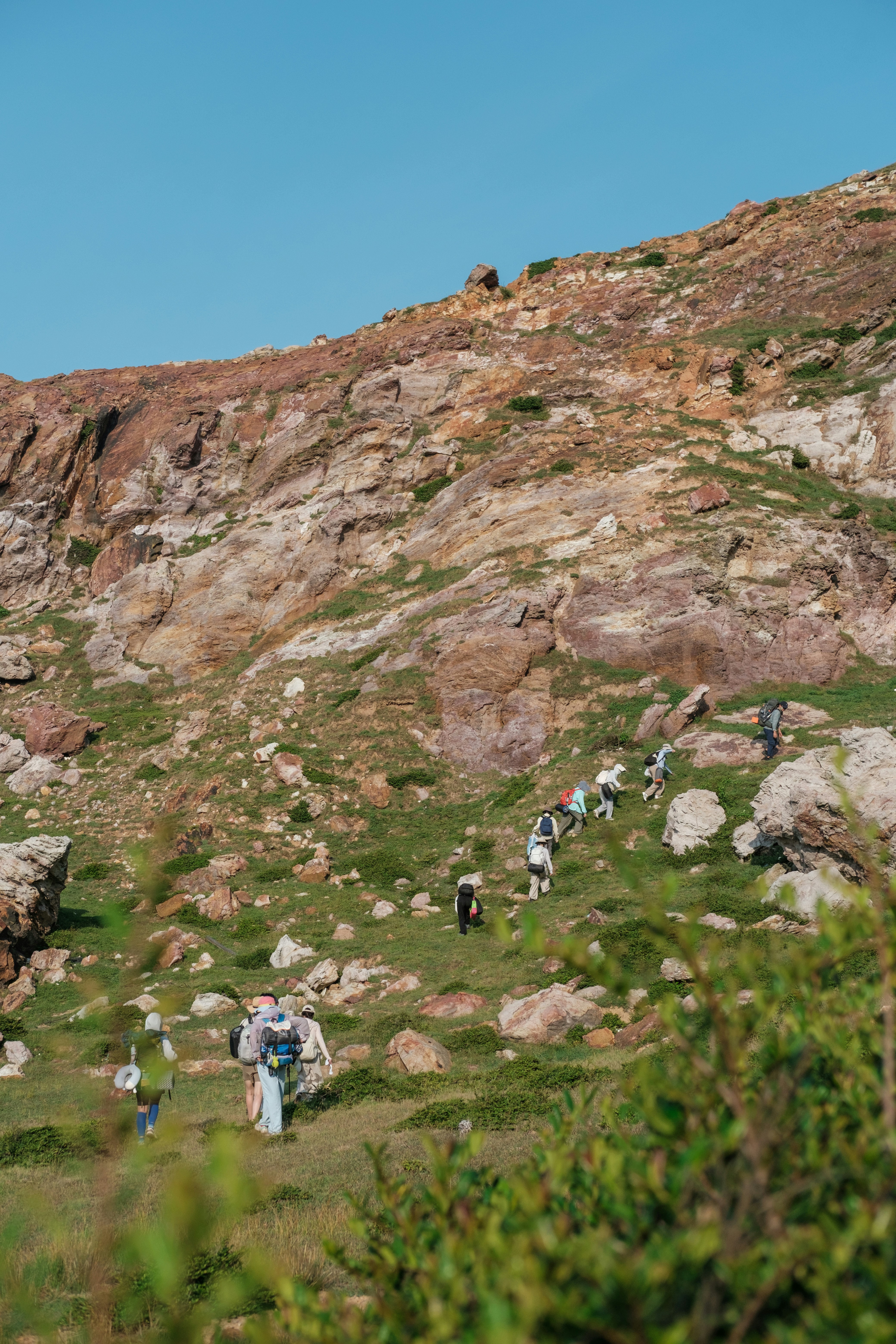 Climbers ascending a sunlit rocky hillside