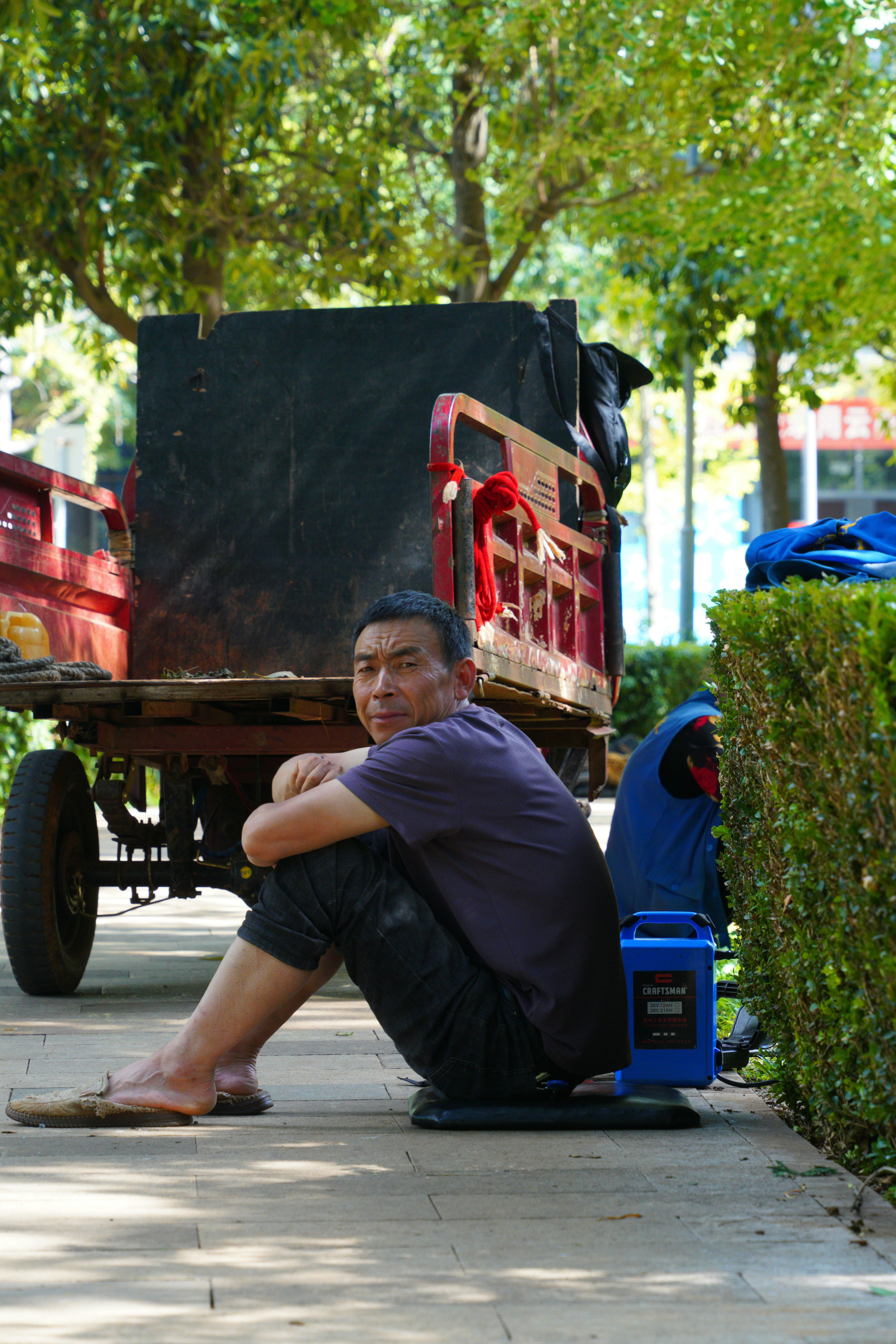 Grounded Pause: A Man Resting Beside a Working Cart