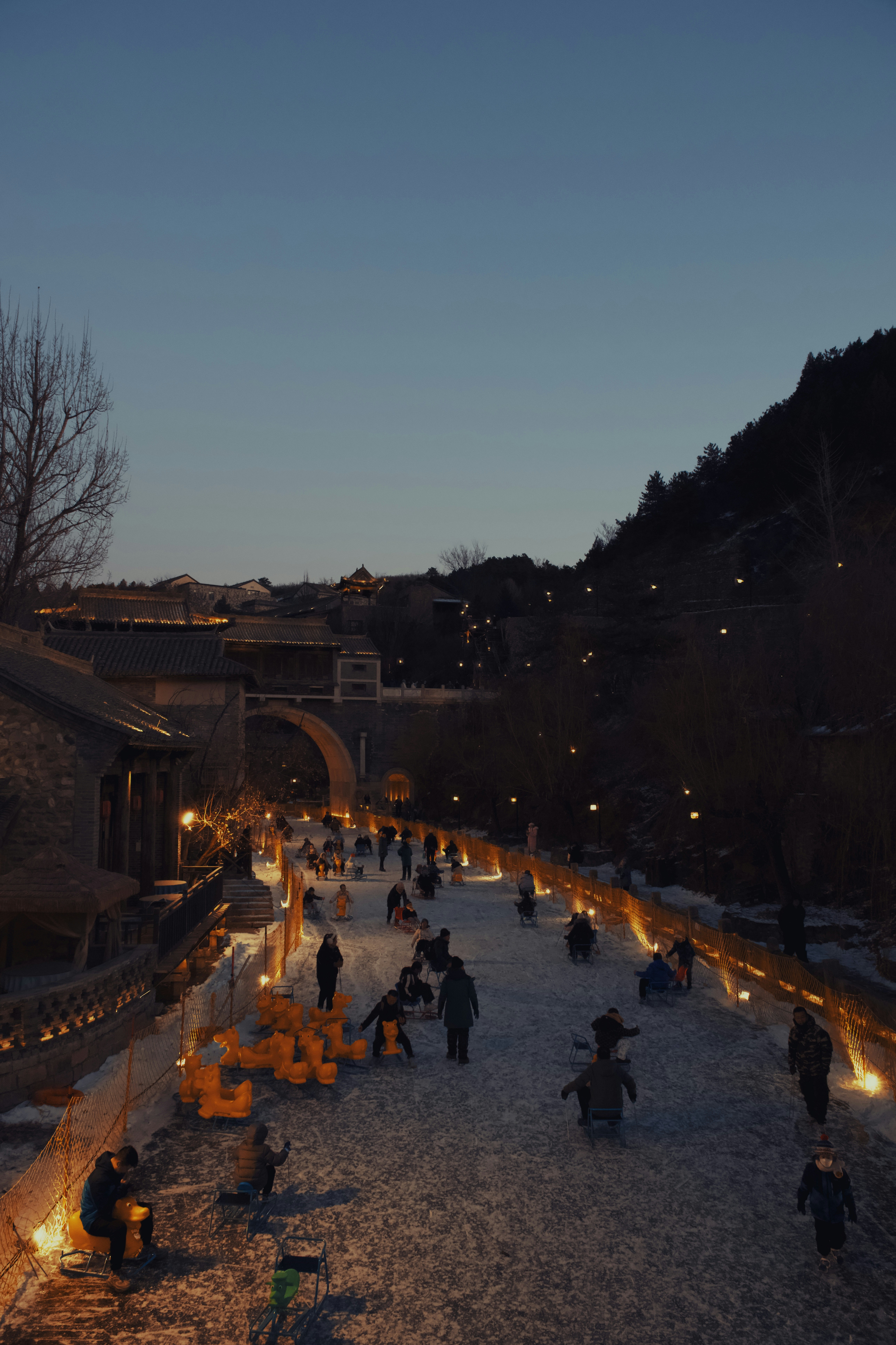 A dramatic blue hour photography of families playing on the top of frozen river at Gubei Watertown, Beijing, China
