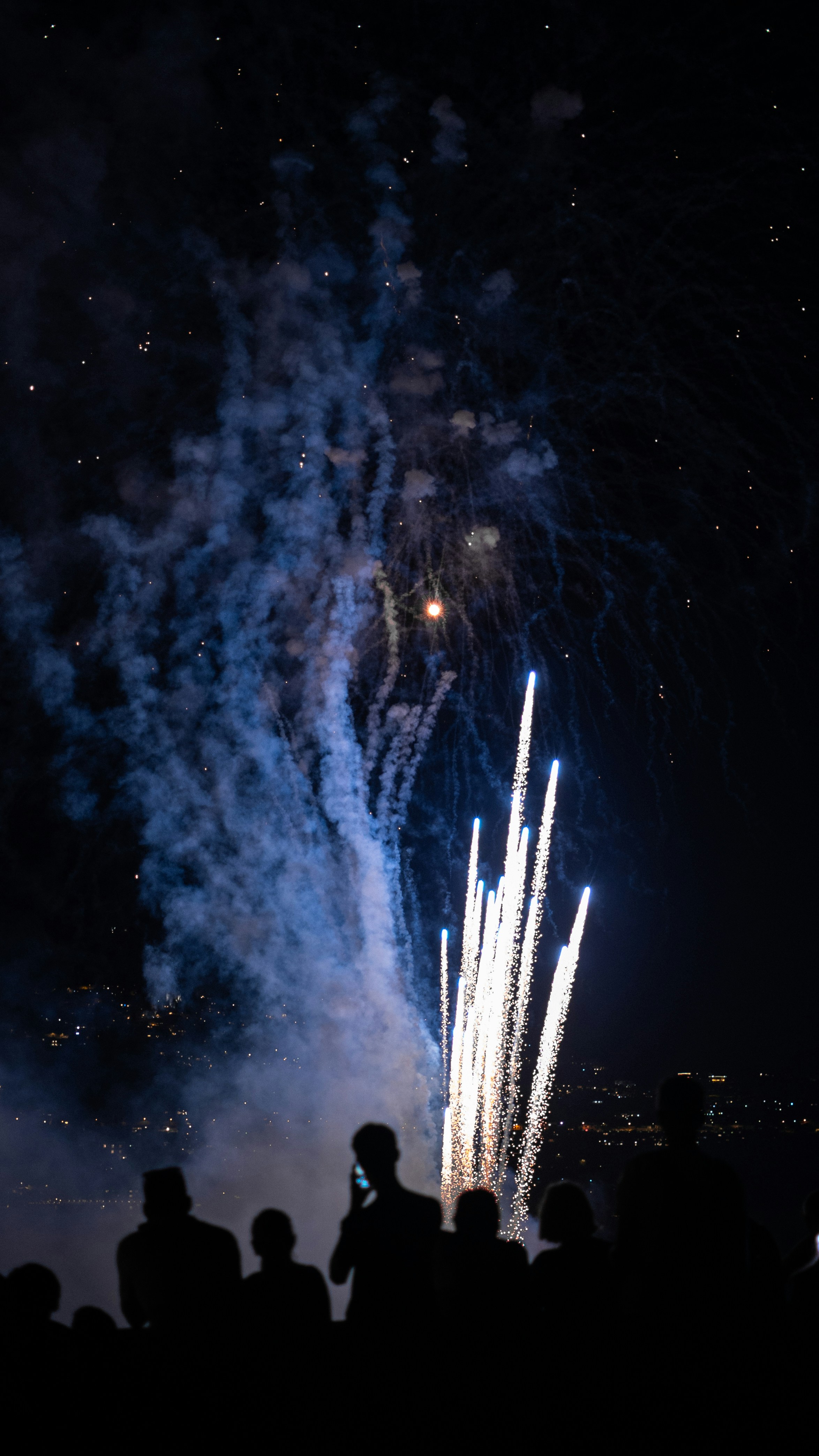 Nightfall Inferno: Firework Arcs Above a Silhouetted Crowd
