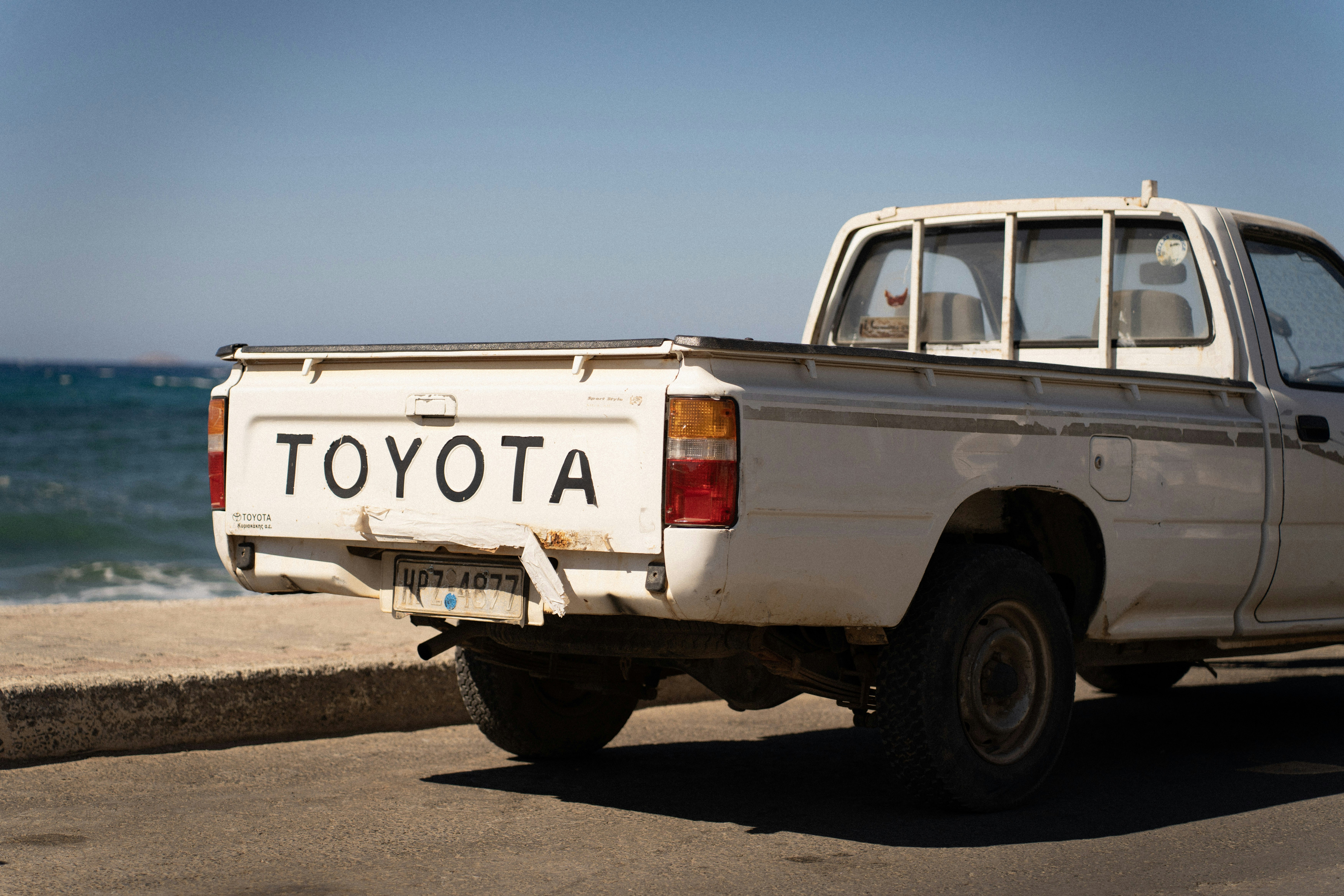 Rear-Quarter Sea Road: A Weathered Toyota waits at memory's edge