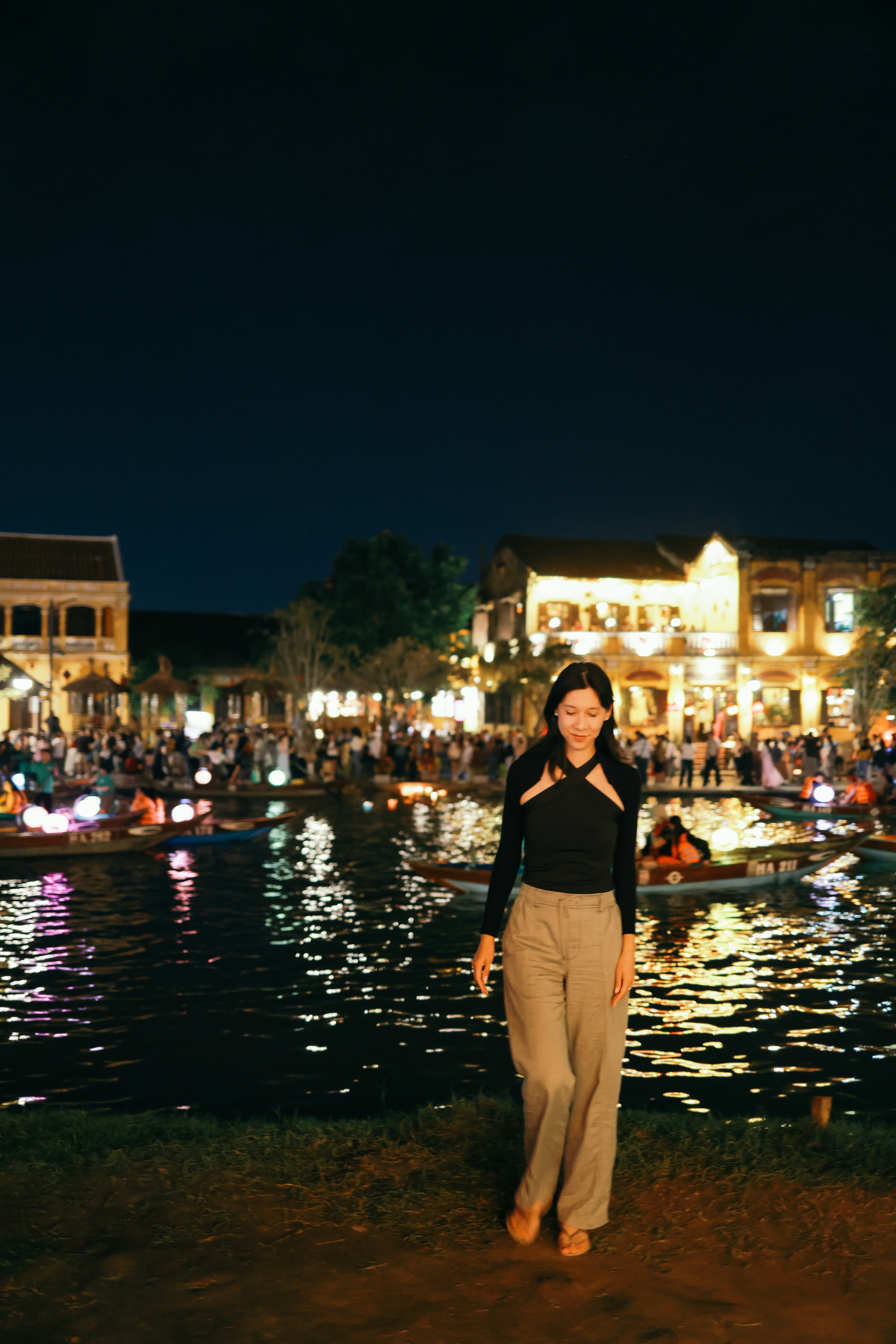 Night stroll along a lantern-lit canal with a poised individual at the water's edge