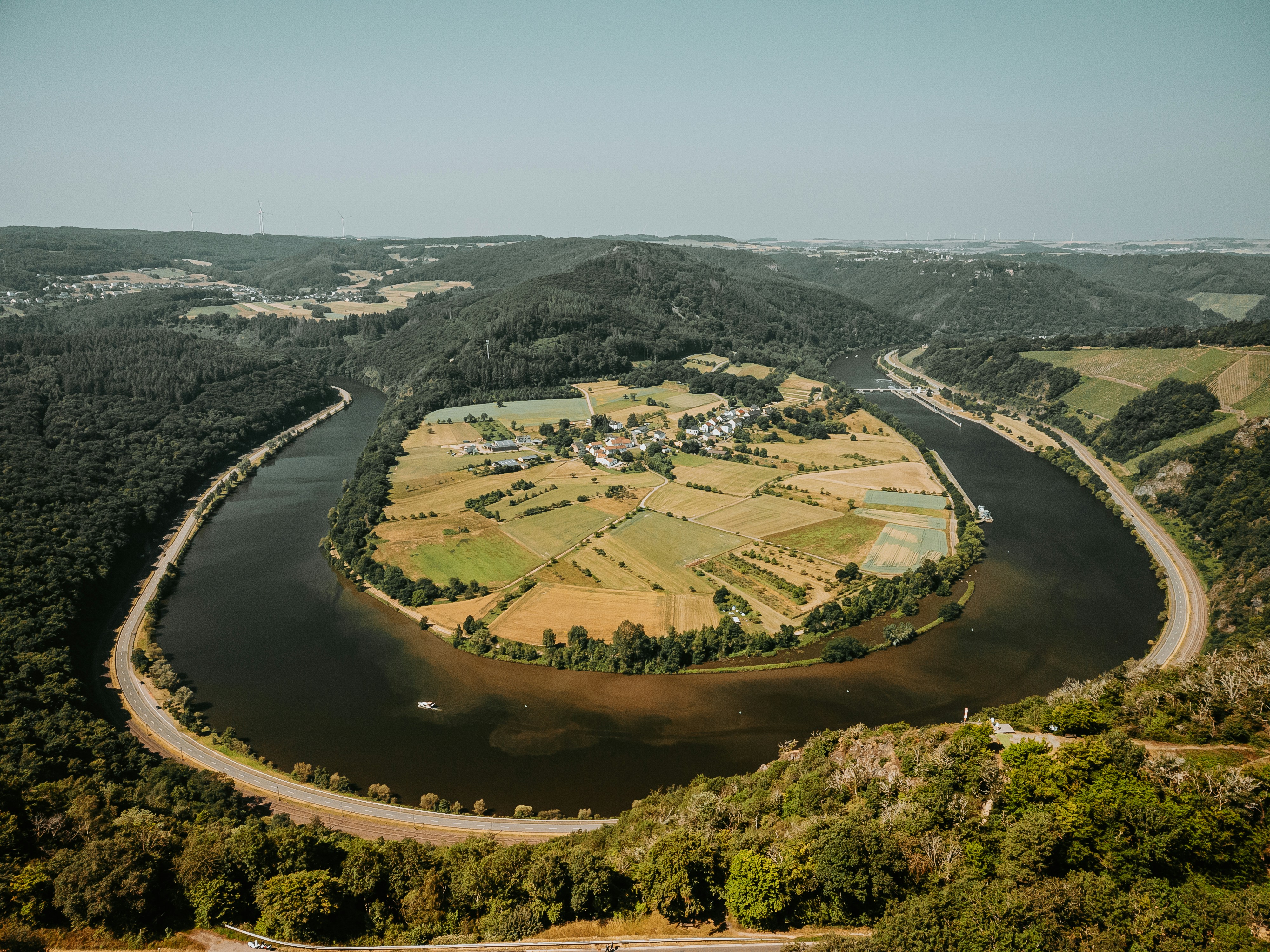 A horseshoe bend river encircles a village and fields.