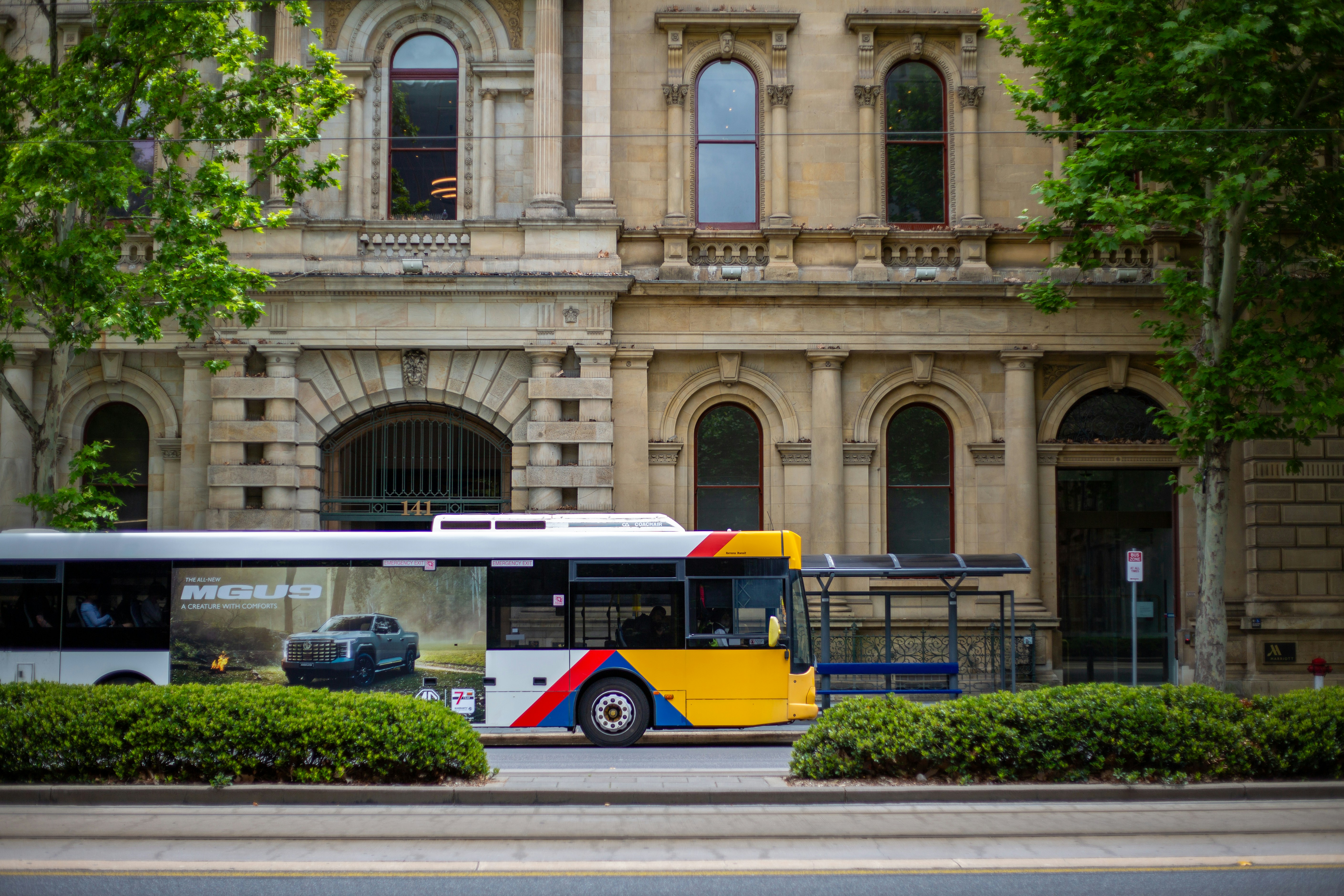 Colorful City Bus Pausing Before a Historic Stone Facade