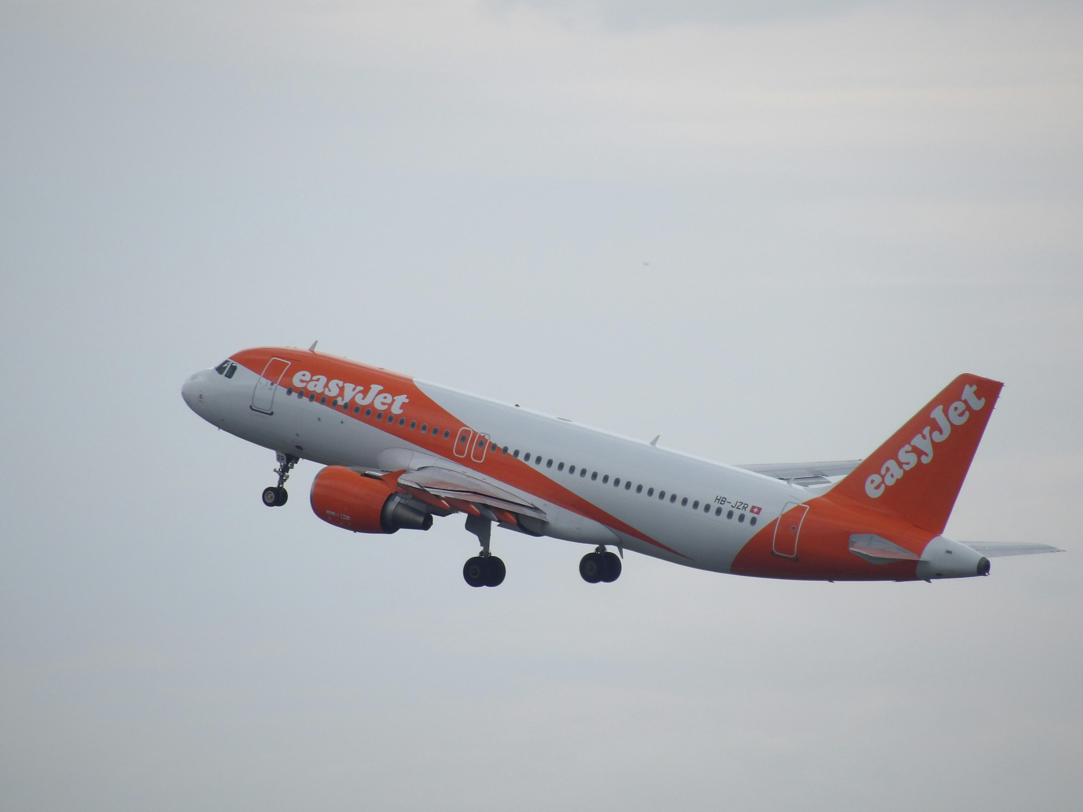 An easyjet airplane taking off into a cloudy sky.