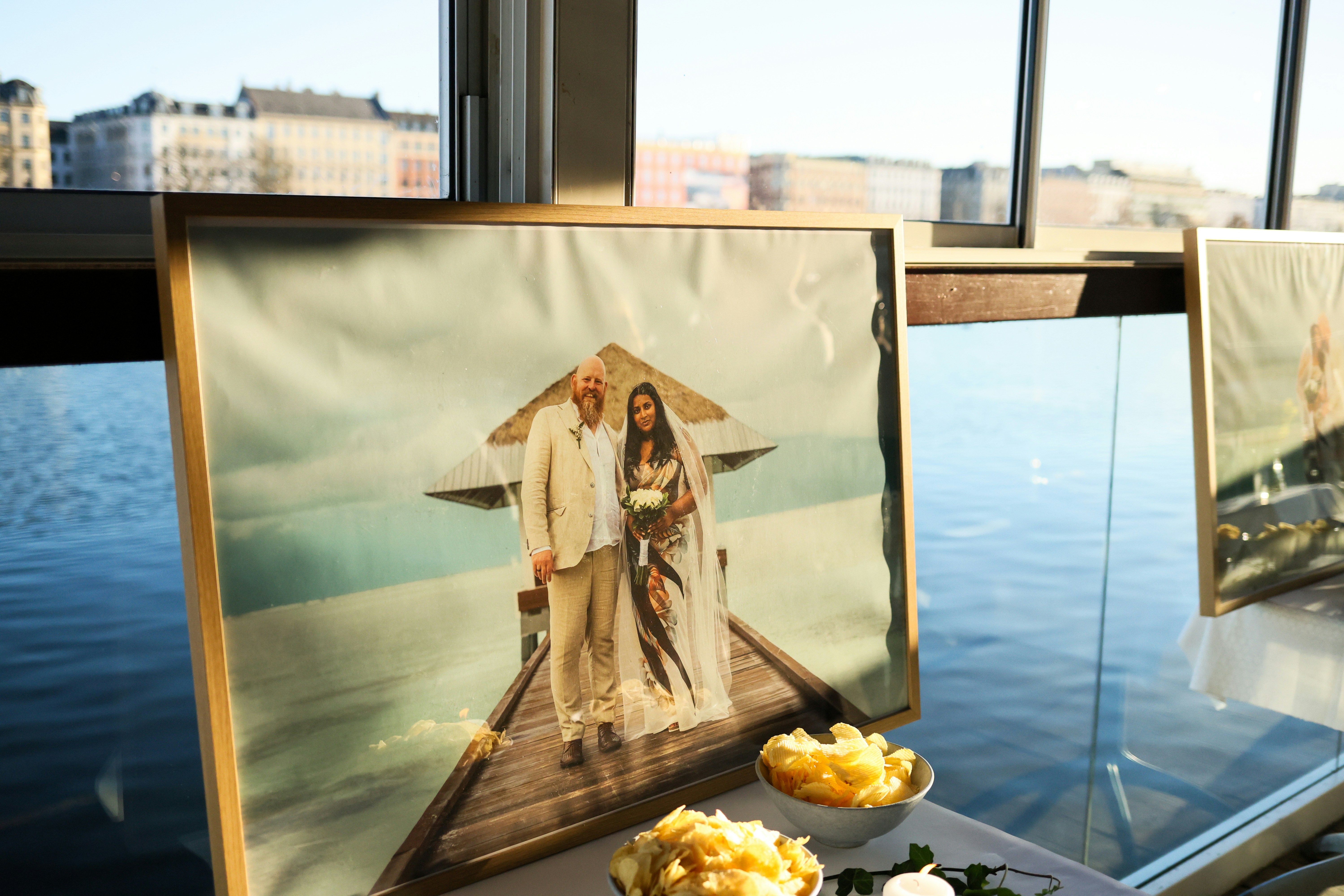 Framed vows by the window: a seaside wedding portrait on display