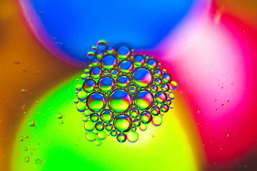 Vibrant macro of clustered bubbles suspended in multicolored liquid, forming a circular core with rainbow reflections; a close-up abstract showing micro-spheres and liquid film textures.
