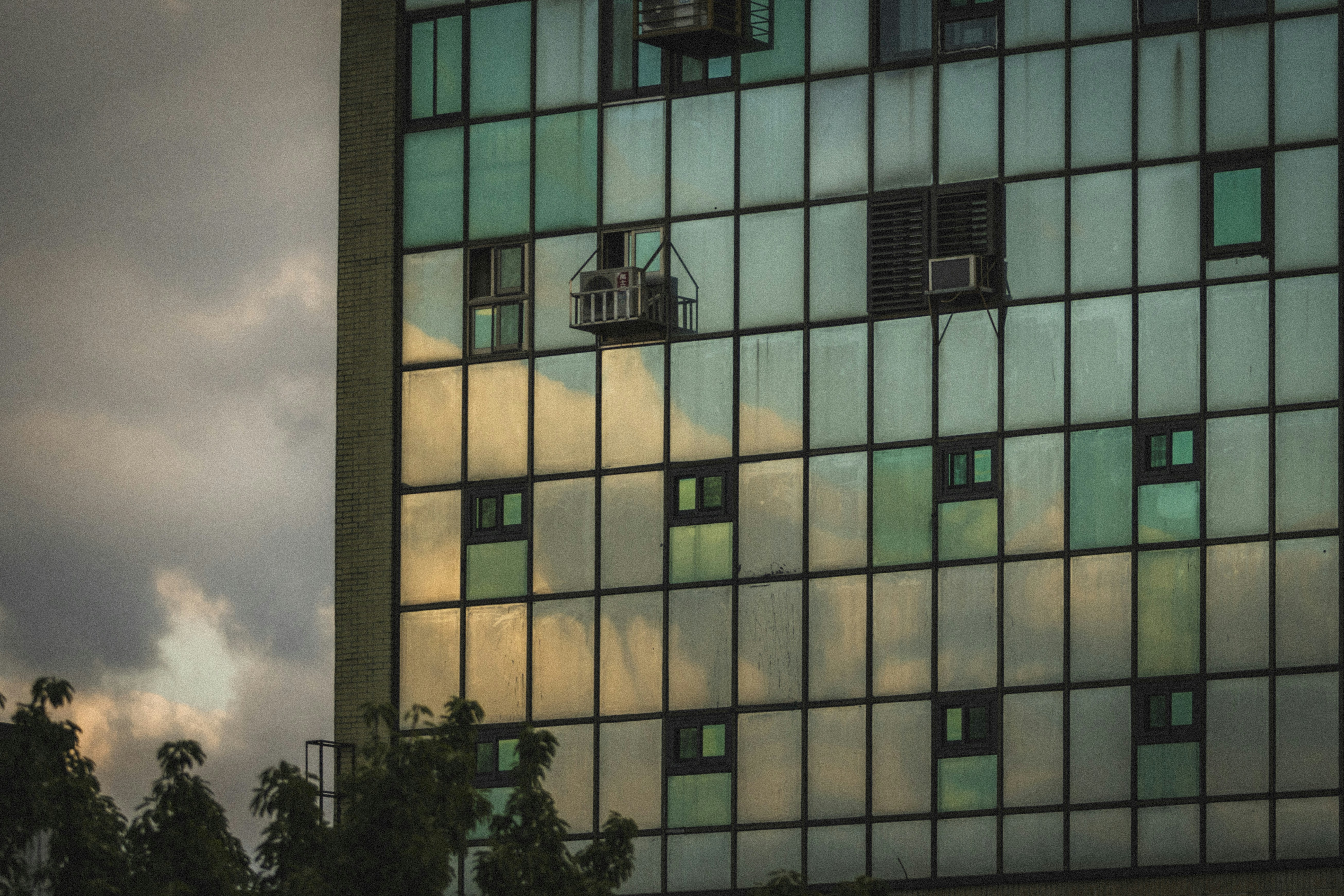 Glass-panel façade reflecting sunset clouds above a lined cityscape