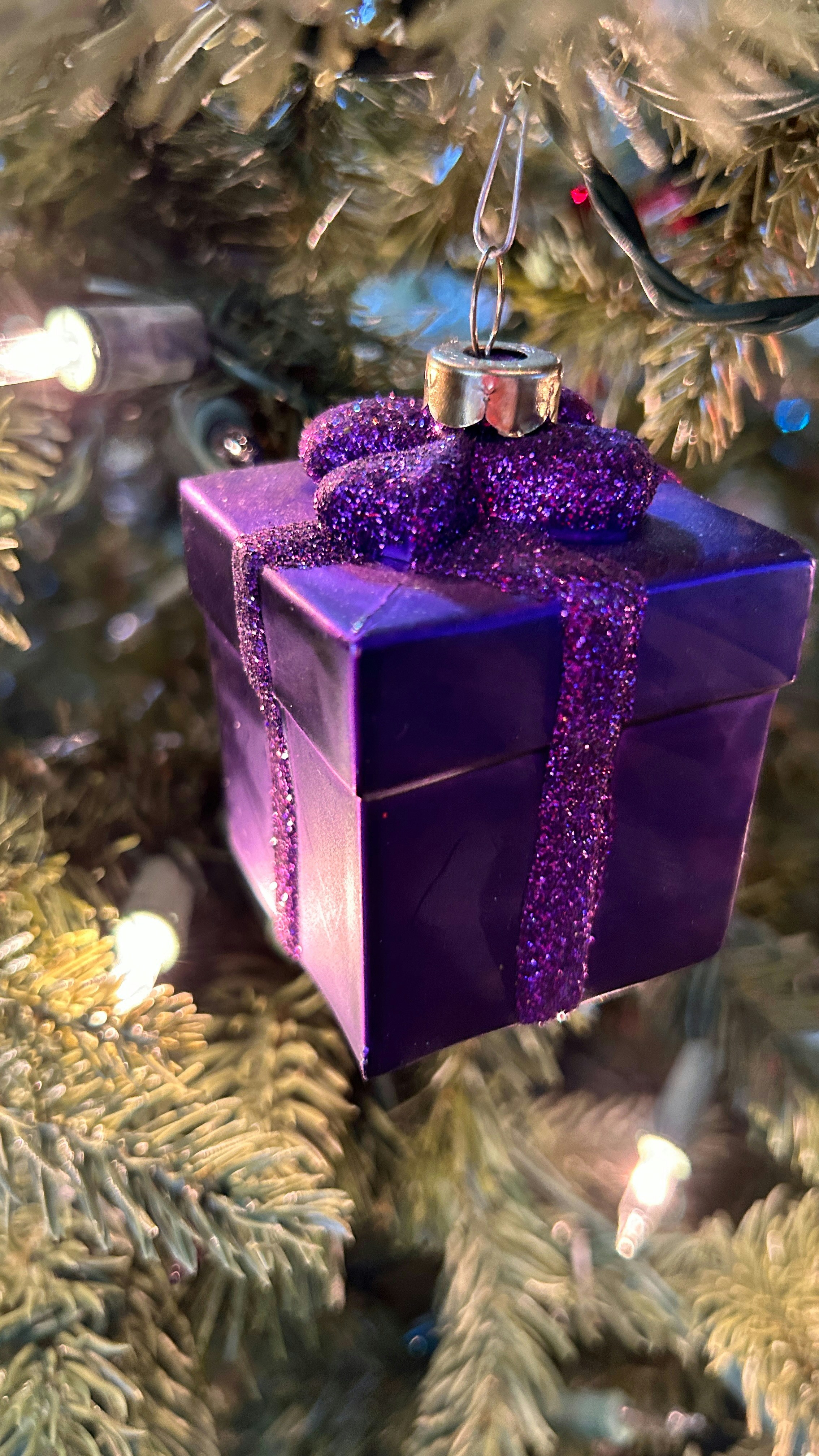 Purple gift box ornament tucked among Christmas needles