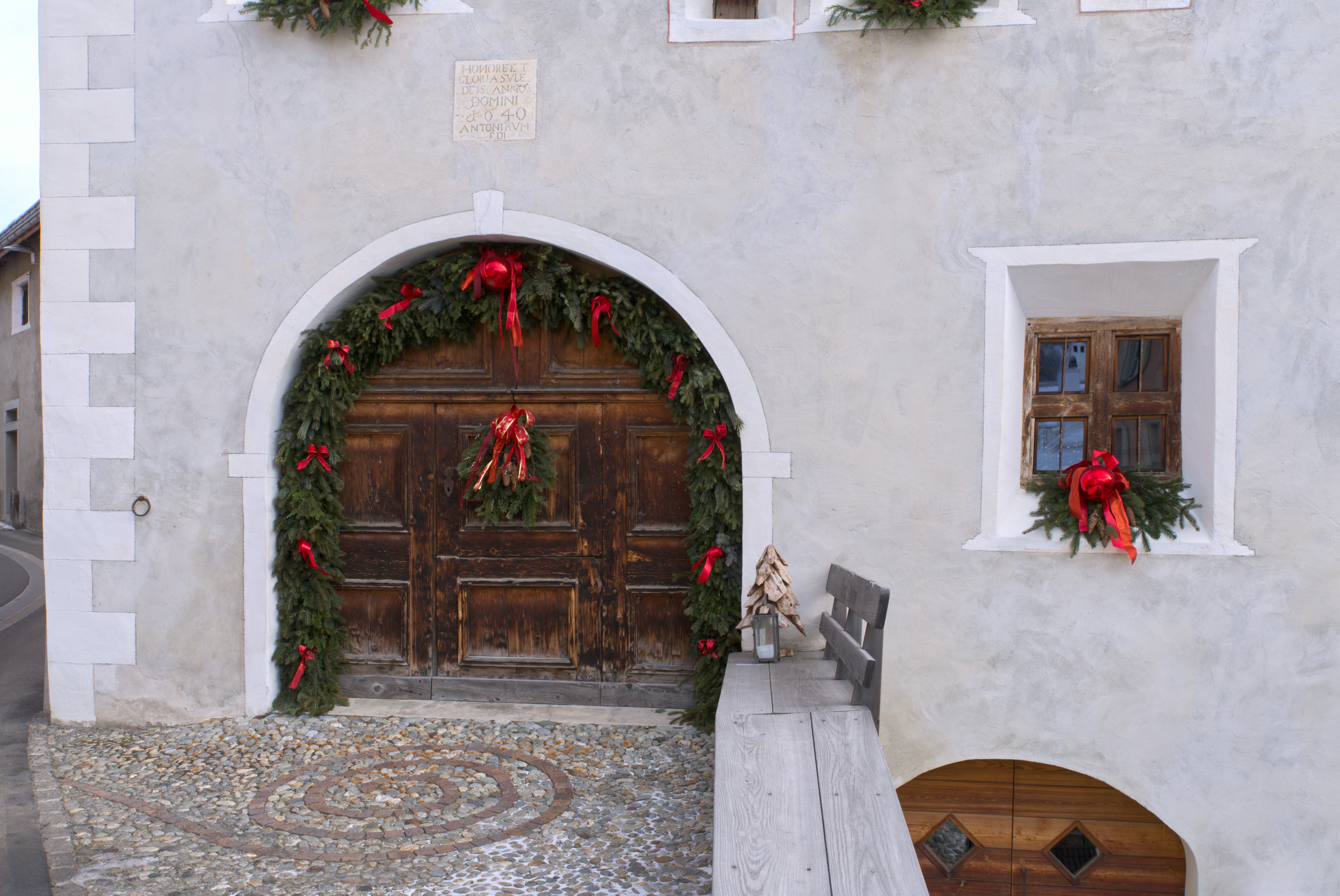Festive doorway framed by greenery and red ribbons under pastel arch
