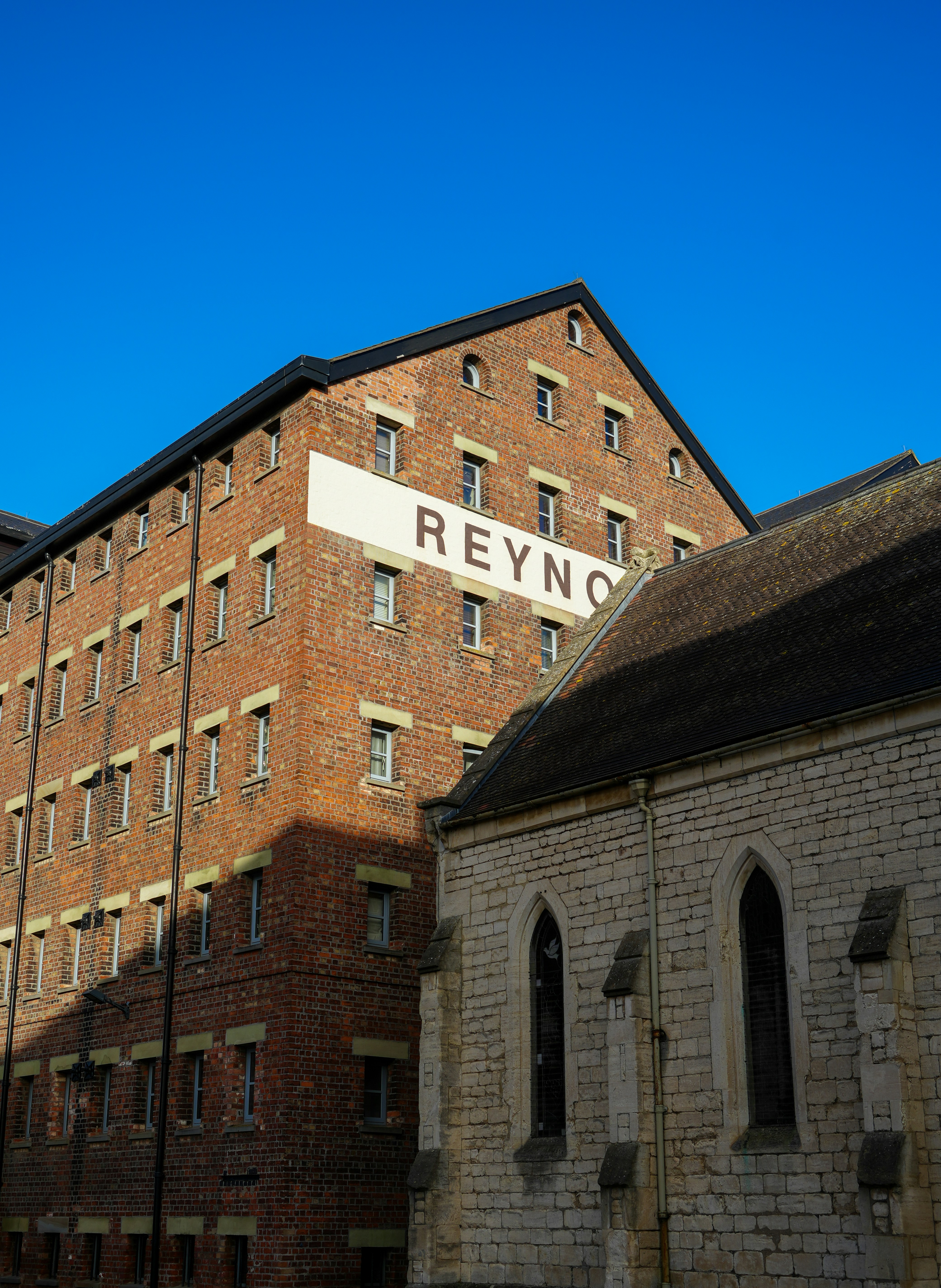 Brick-and-stone edifice with a bold REYNO sign under a clear blue sky