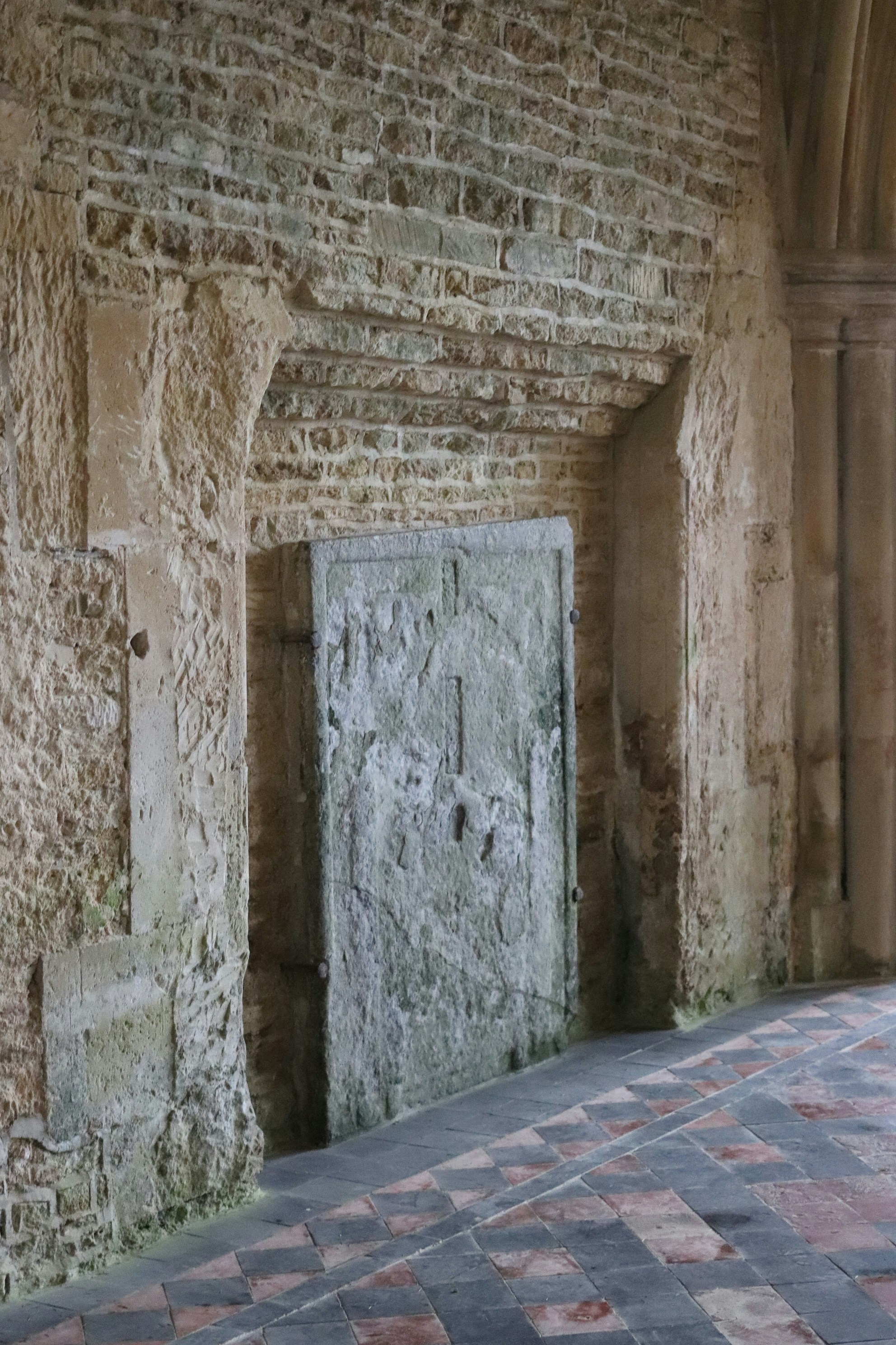 Ancient doorway in sunlit cloister carved from weathered stone