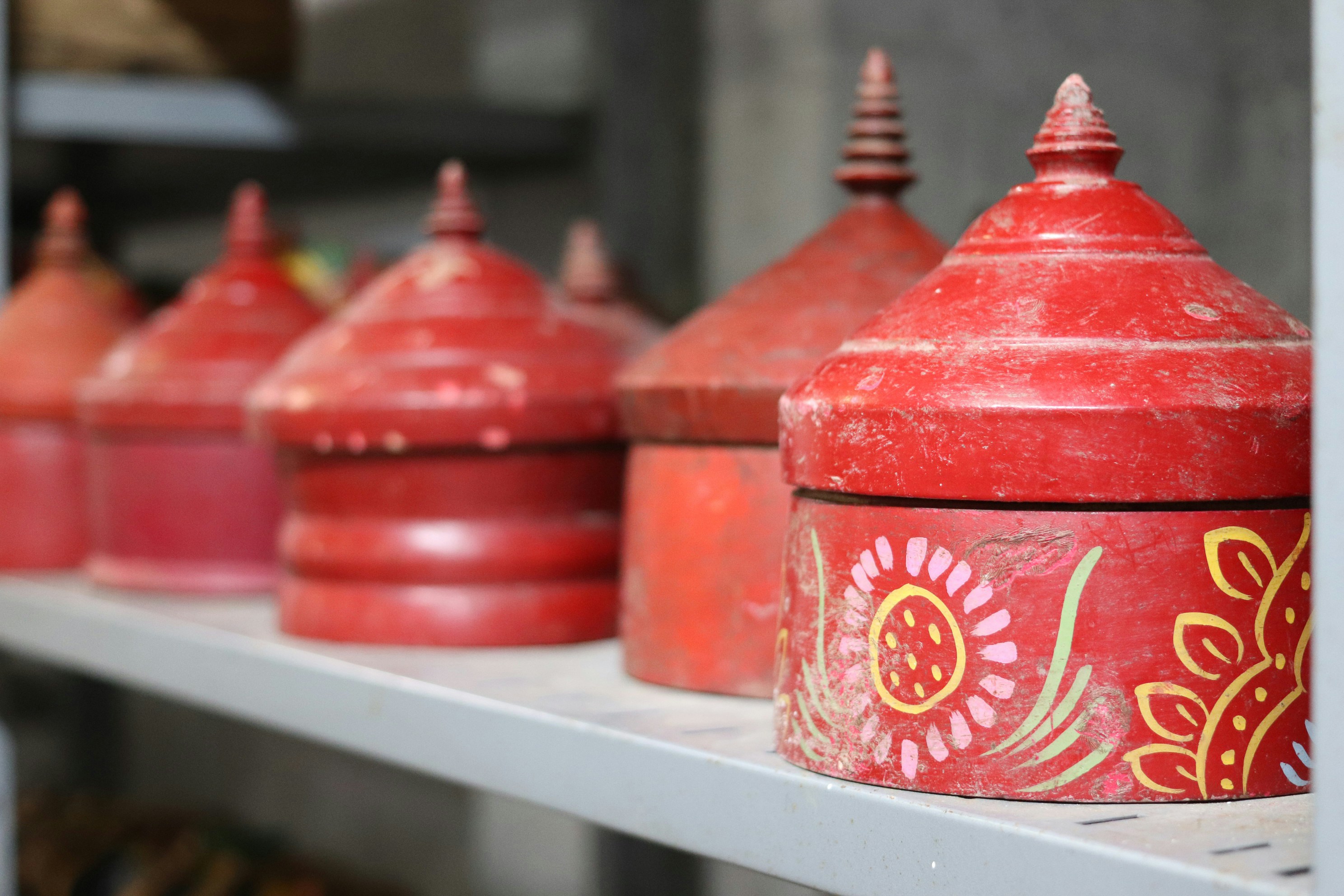 Row of red decorative containers with floral patterns. photo – Free ...