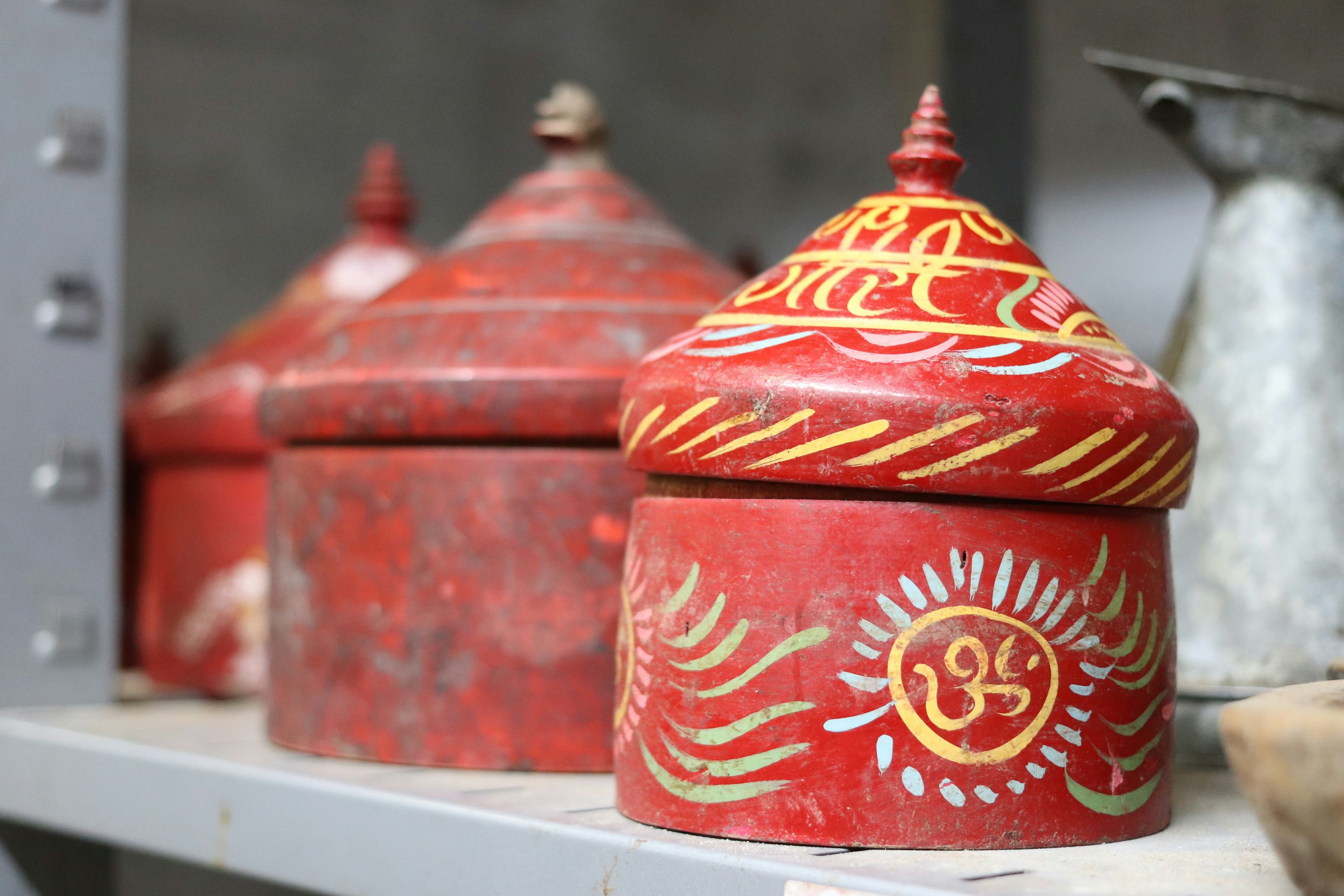 Red Tin Cones: A Row of Ornate Containers on a Workshop Shelf