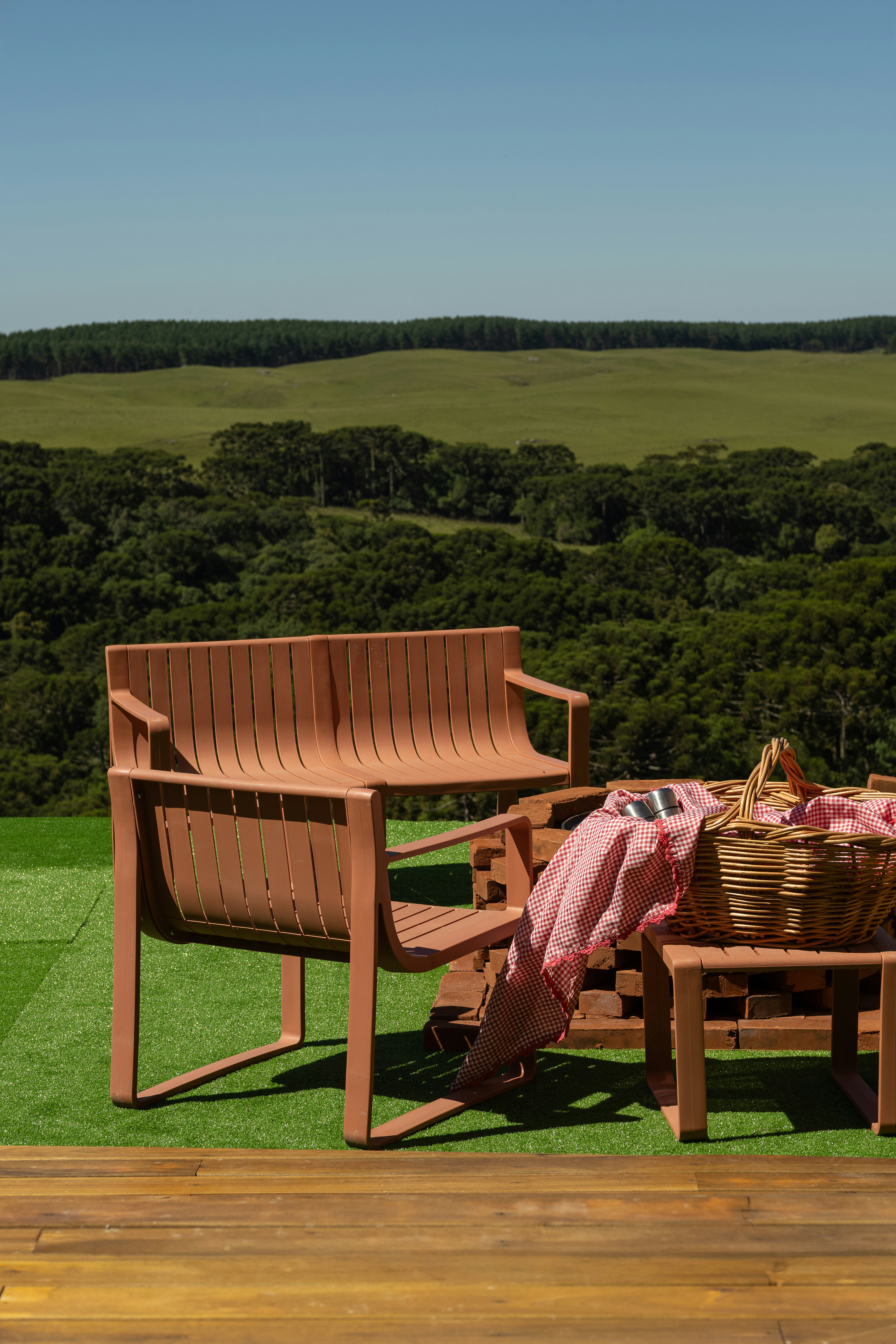 Picnic by the Hills: Wooden Bench and Basket on a Sunlit Lawn