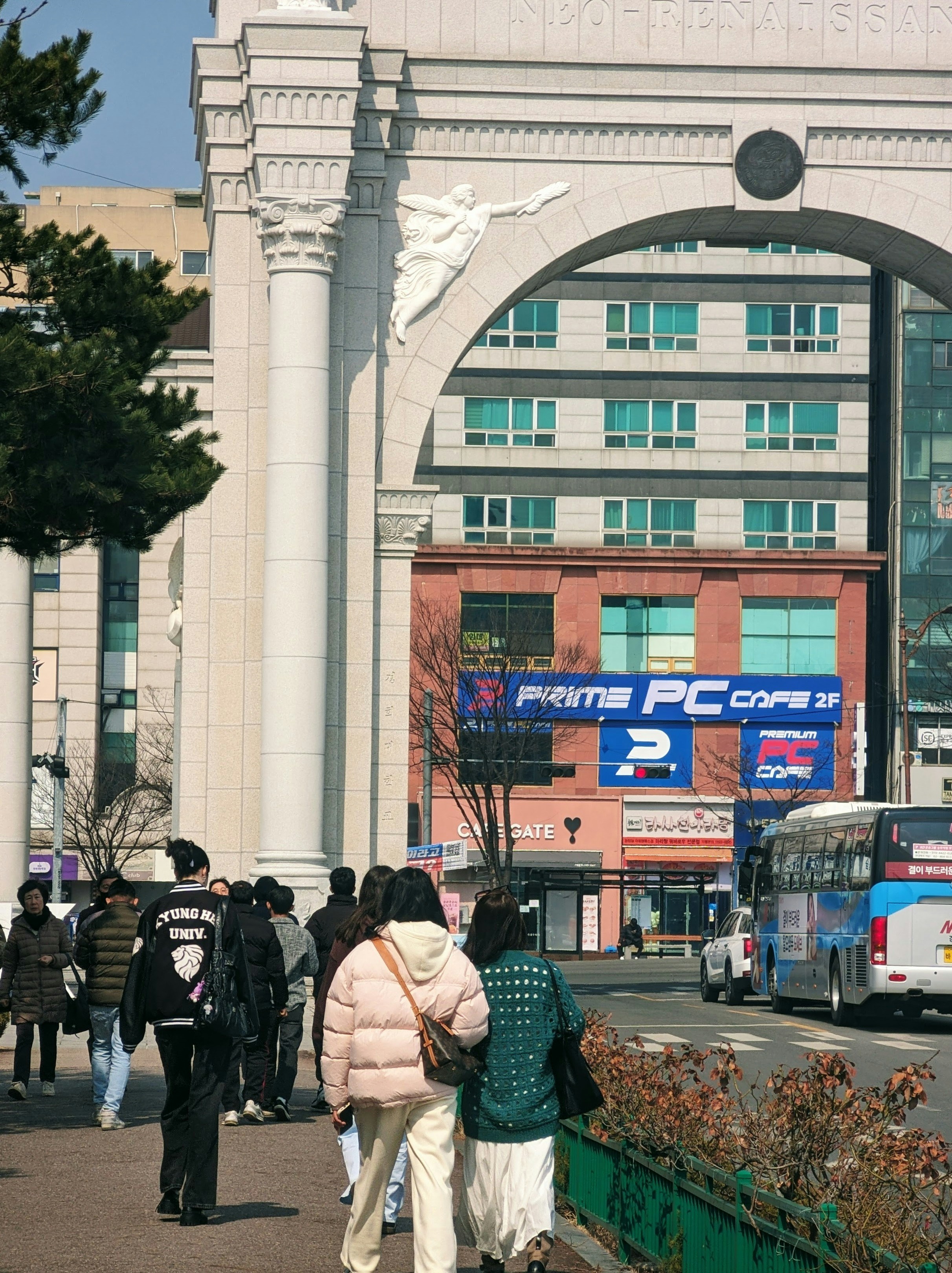 People walking on a city street under an archway
