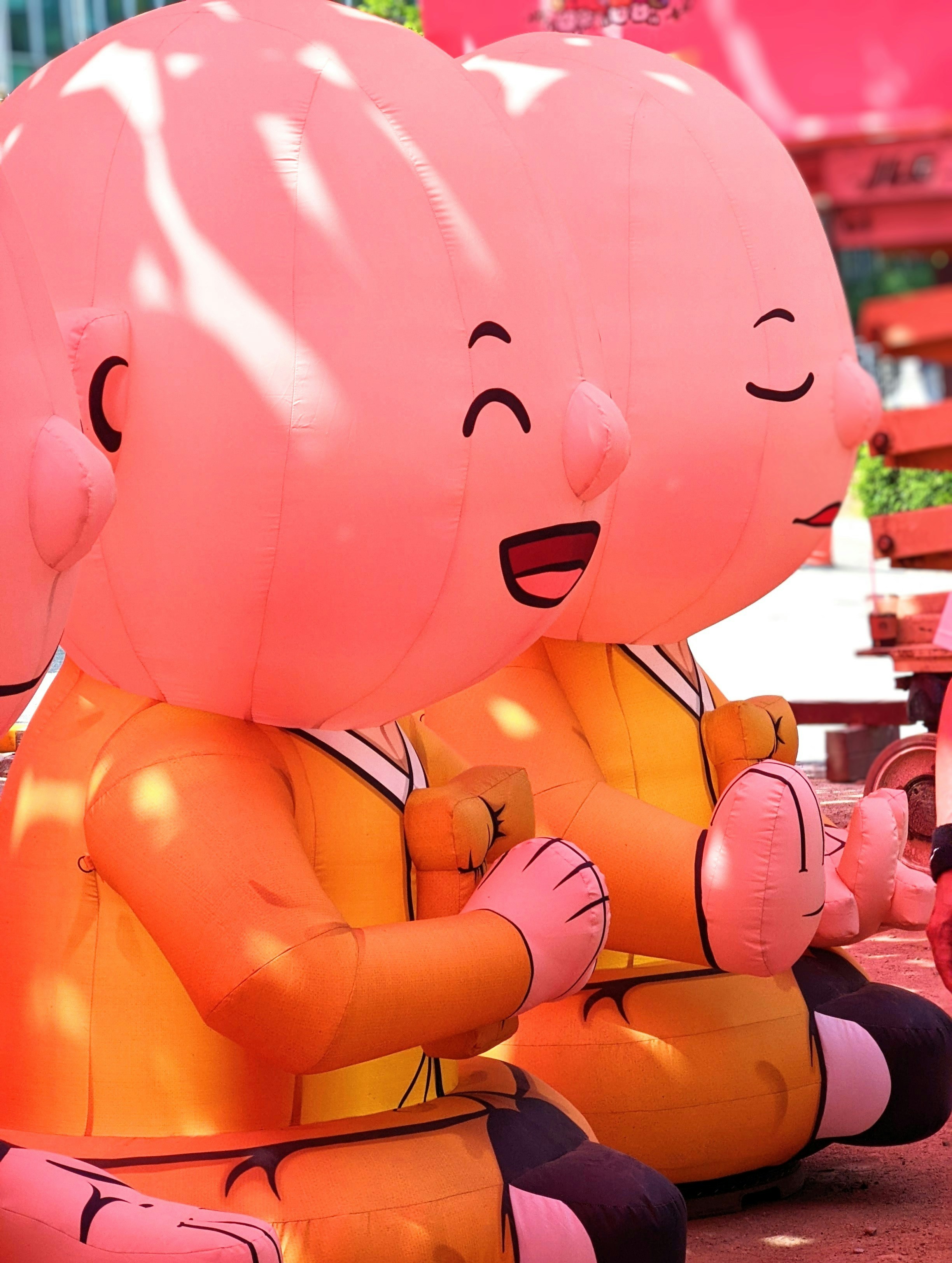 Two inflatable cartoon monks sitting in prayer.