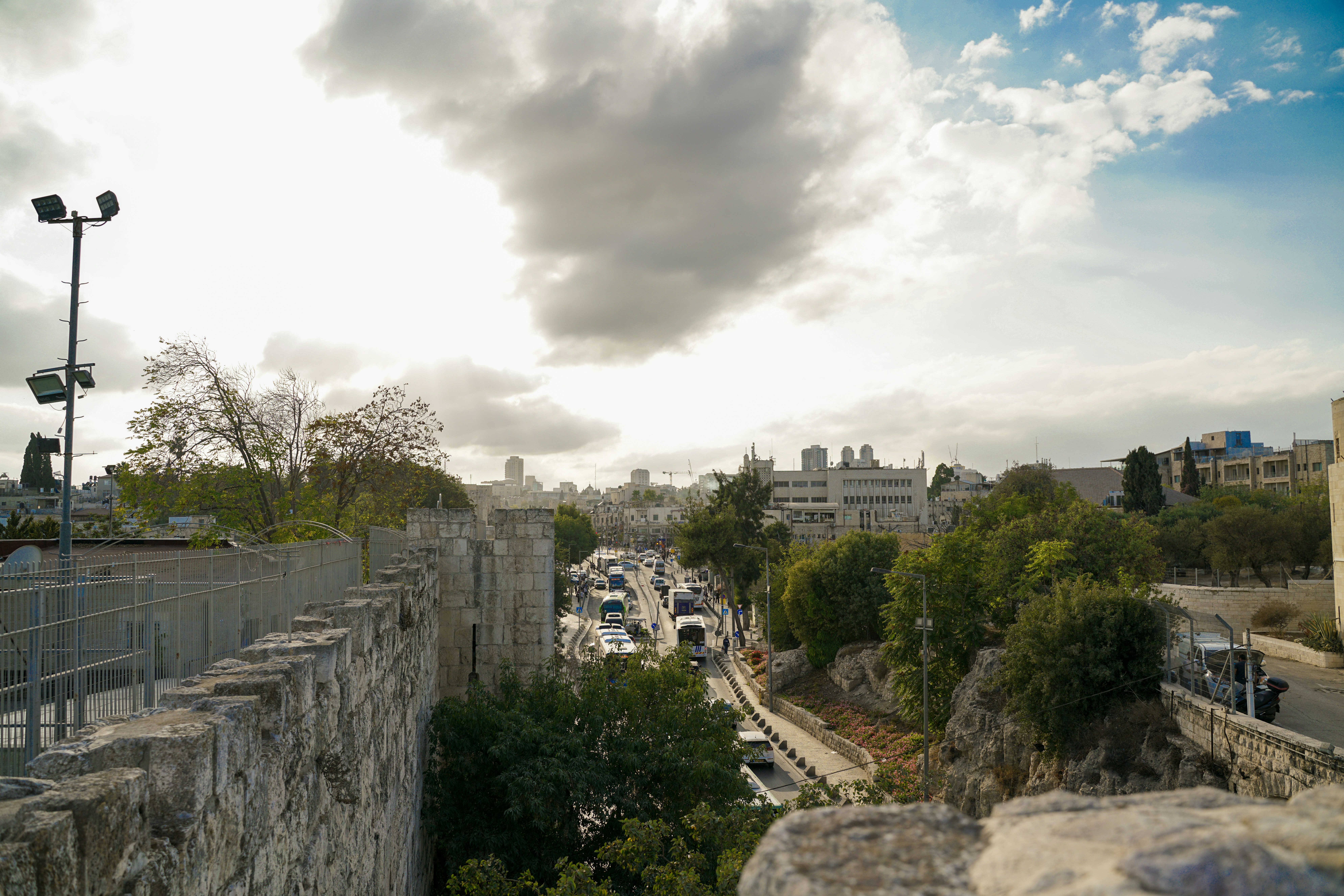 Ancient walls, modern cityline: a sunlit avenue framed by stone in a sunlit overlook