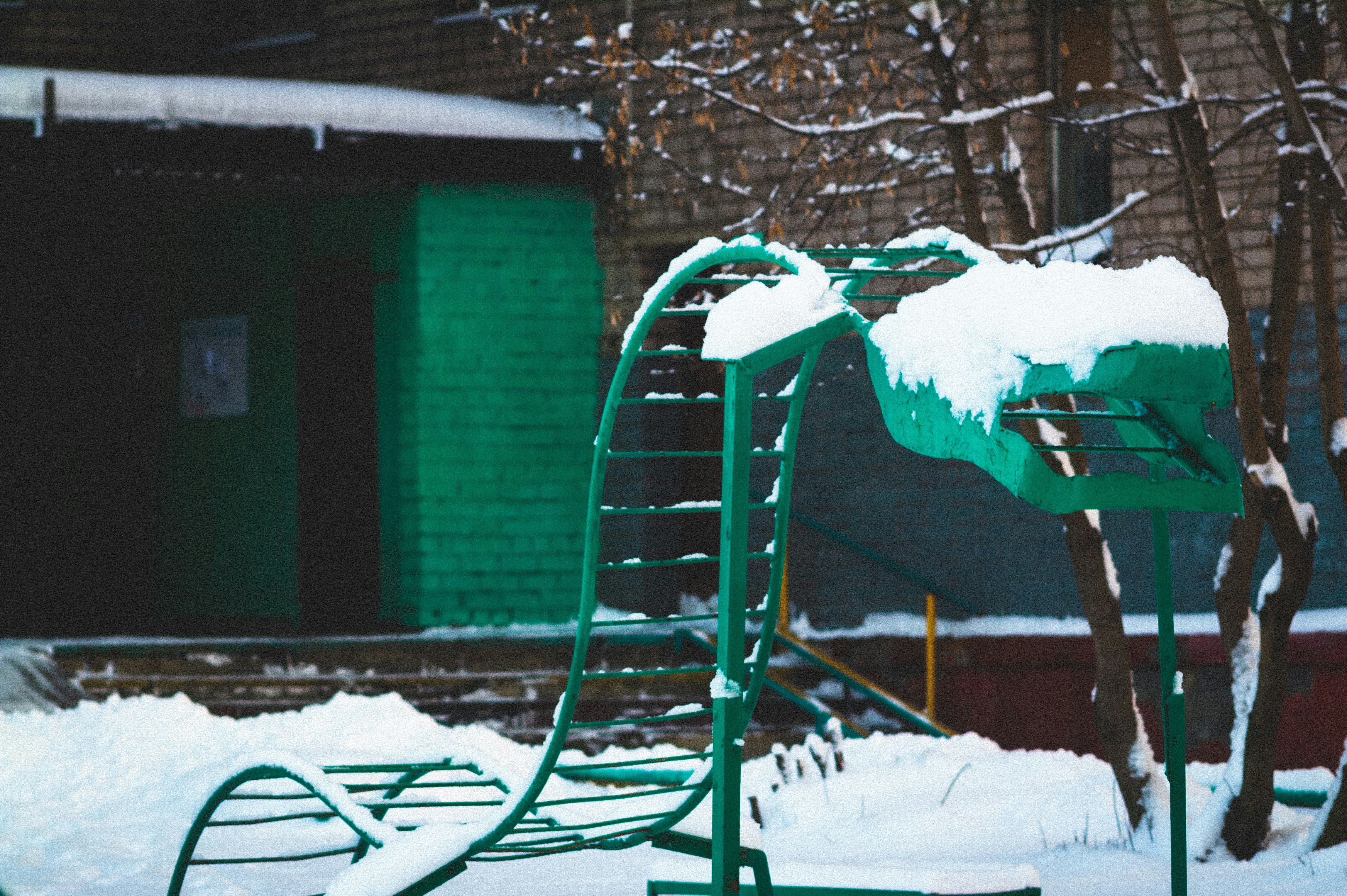 A green playground structure covered in snow.