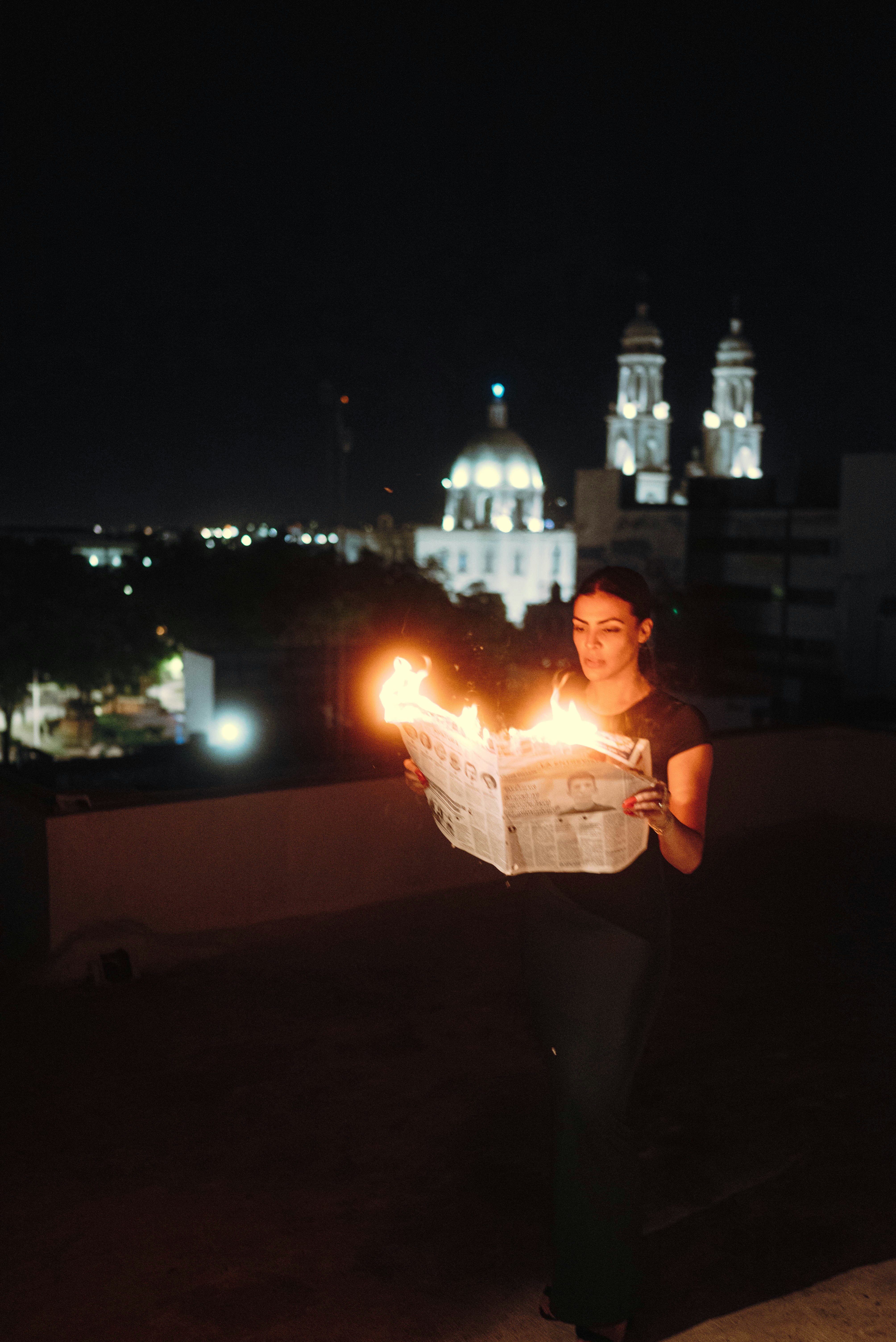 Flame-lit Reader on a Rooftop Beneath Cathedral Towers