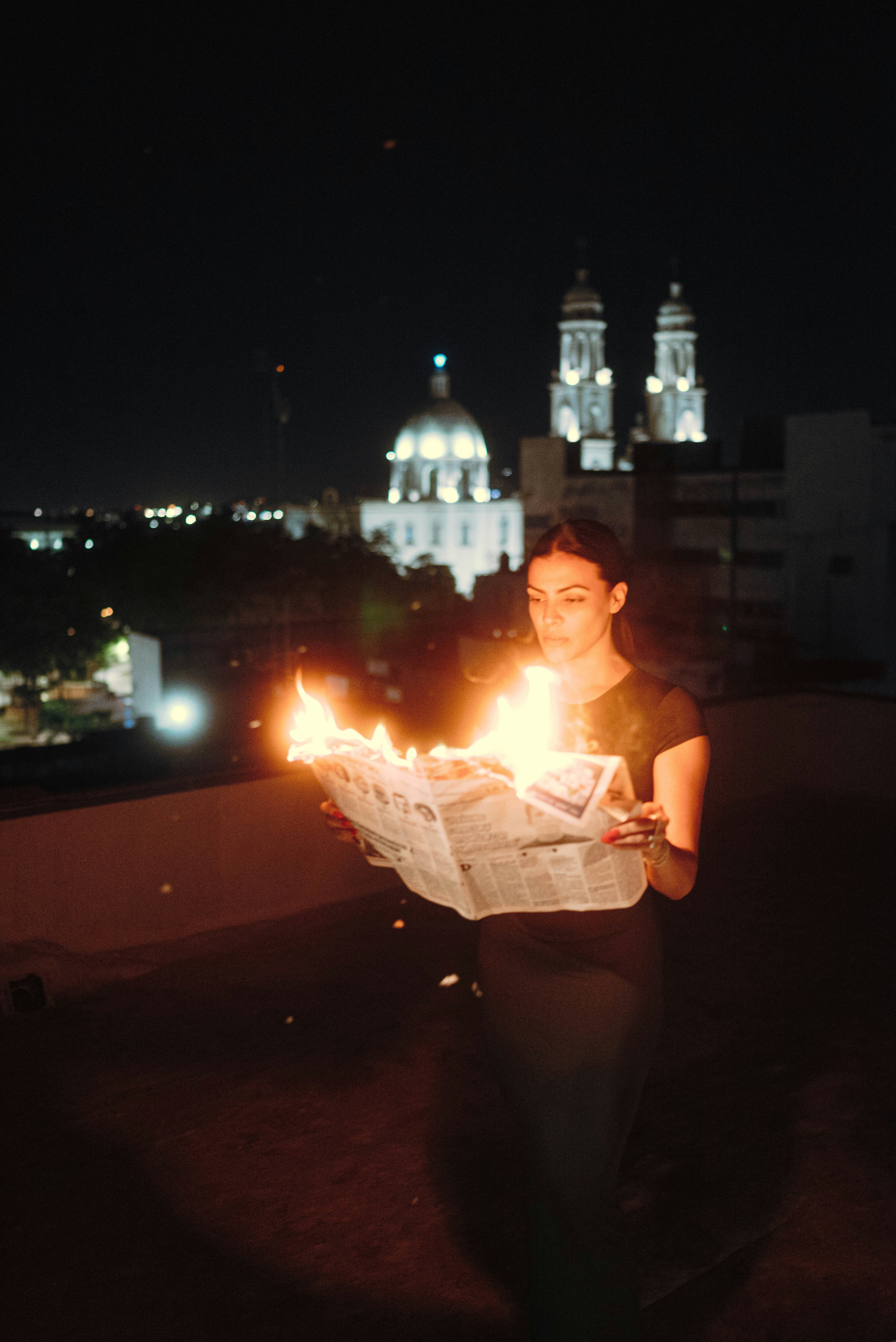 Flame-lit Newsprint on a Night Rooftop