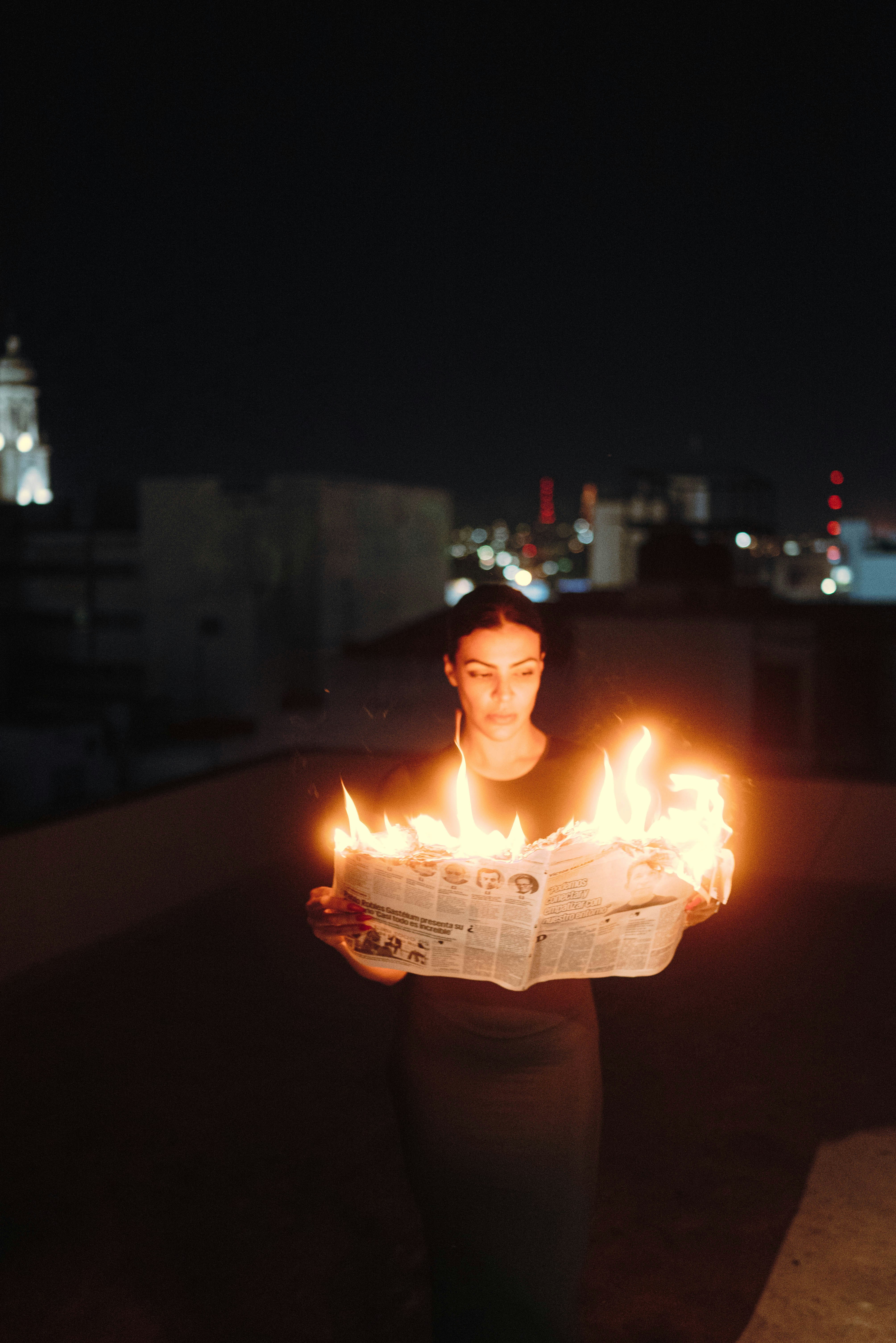 Night Flame: A Woman Weighs Light on a Fiery Newspaper