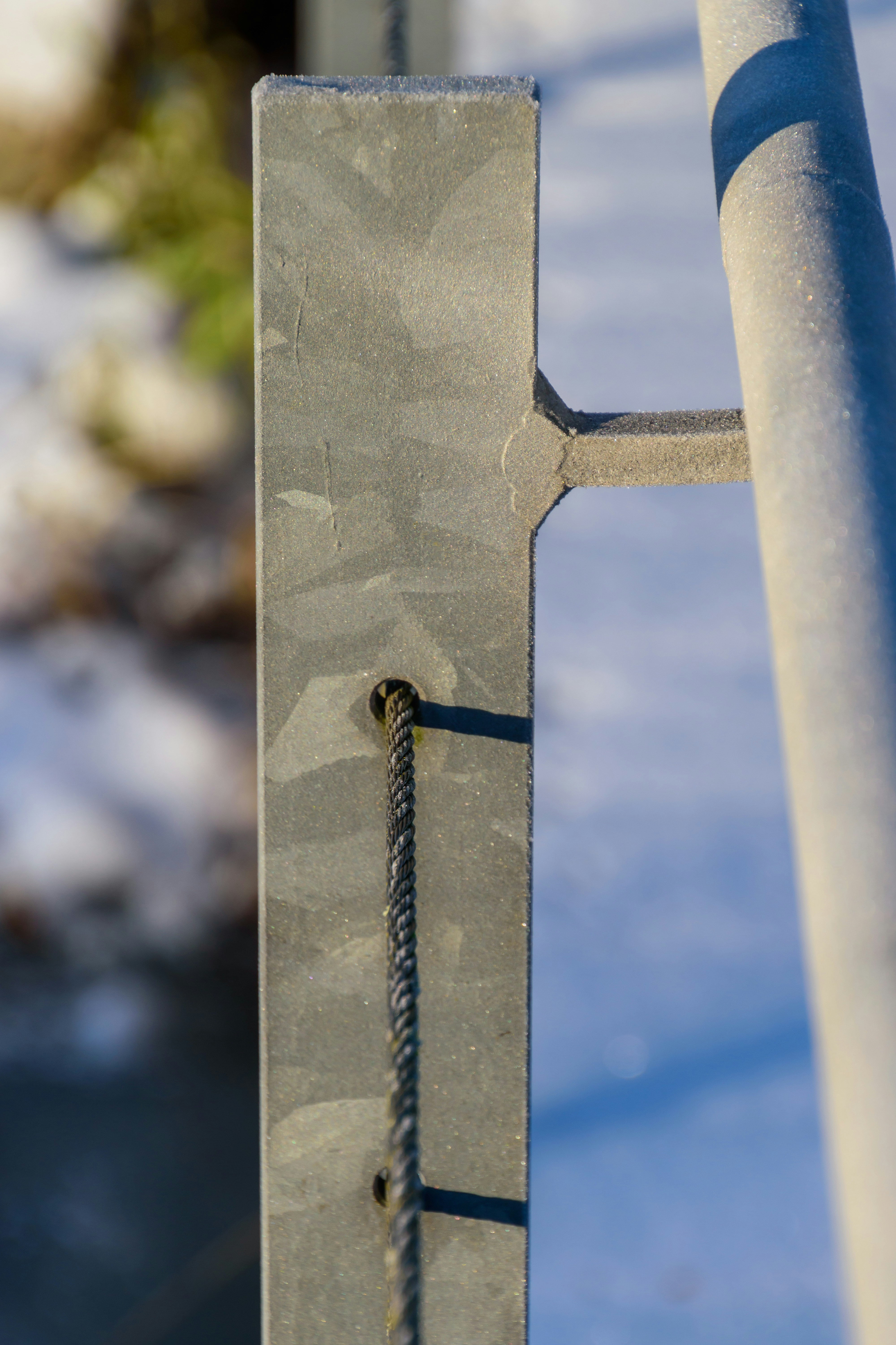 Close-up of a weathered metal frame and rope in cold sunlight