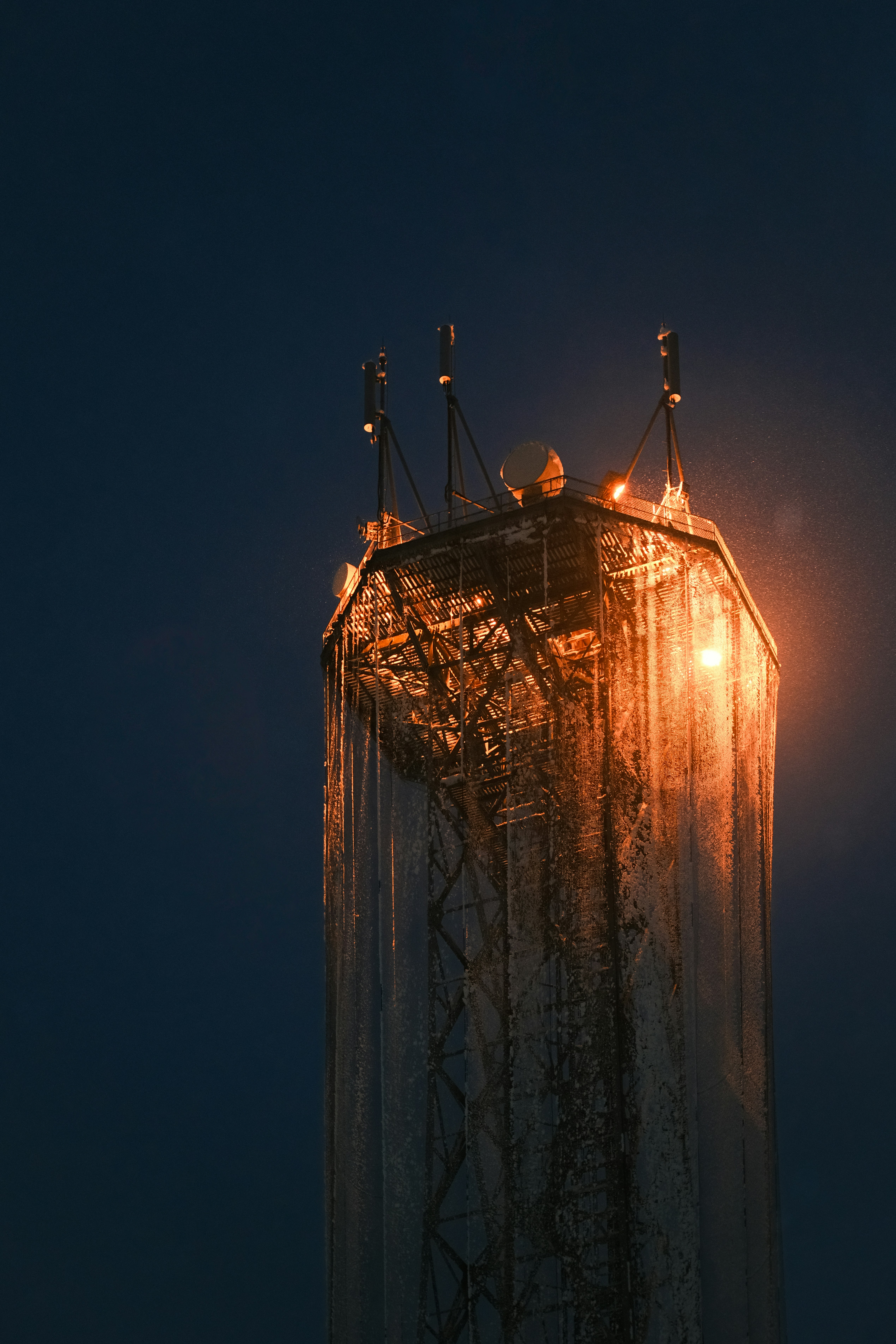 Ice-coated beacon under night glow: a solitary tower frozen in amber