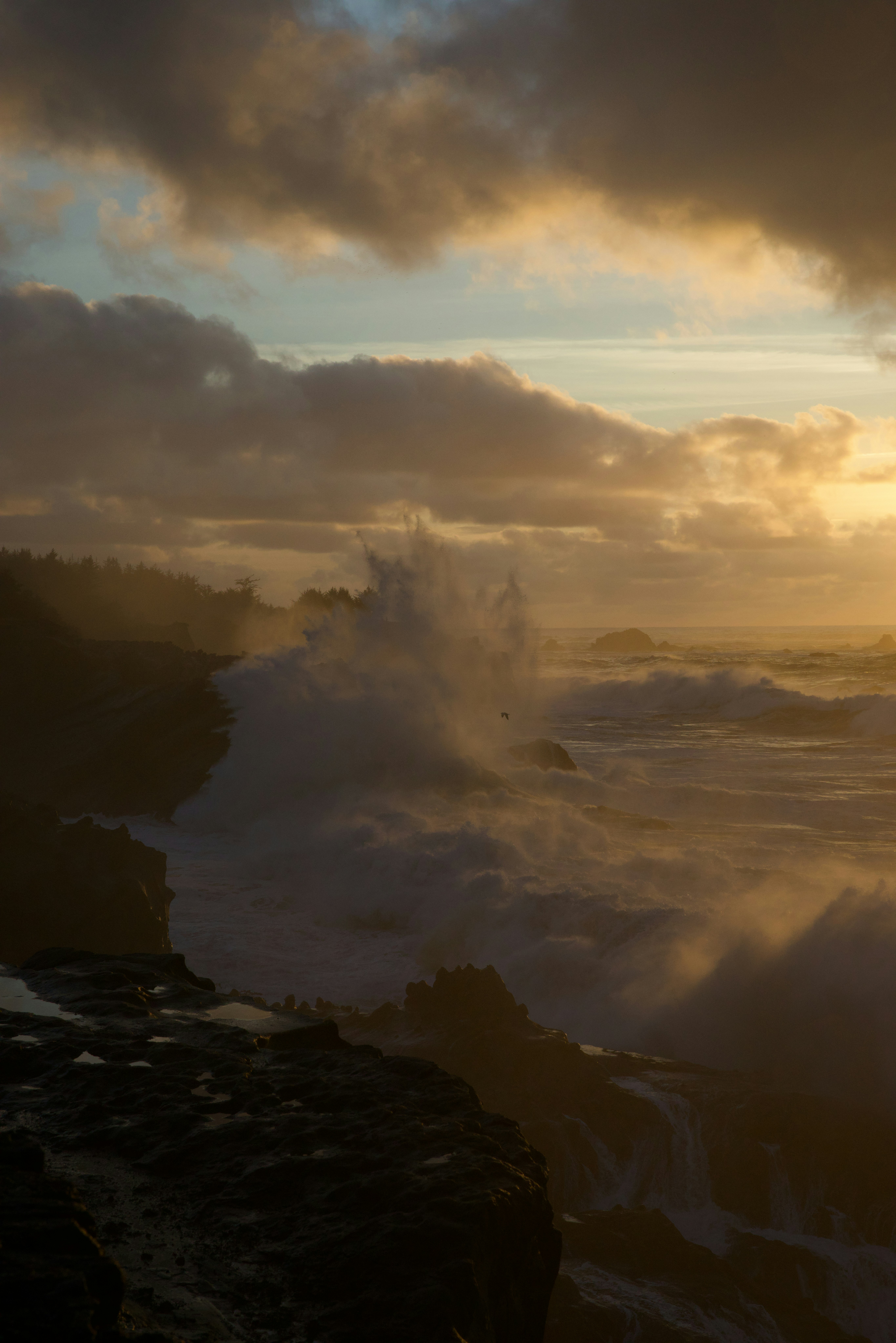 Olas oceánicas agitadas rompiendo contra la costa rocosa al atardecer ...