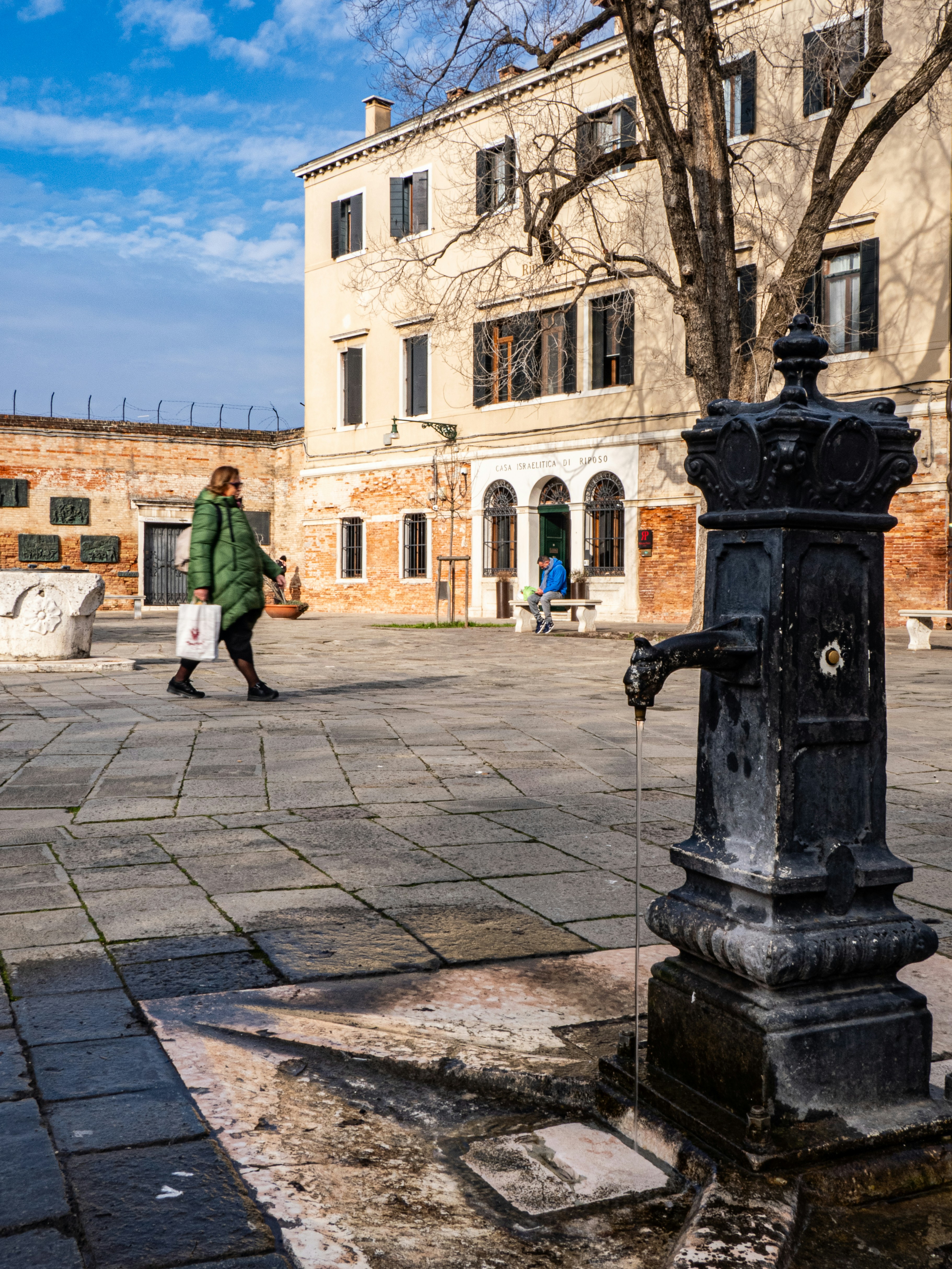 Courtyard Fountain and Passing Pedestrians outside a Historic Building