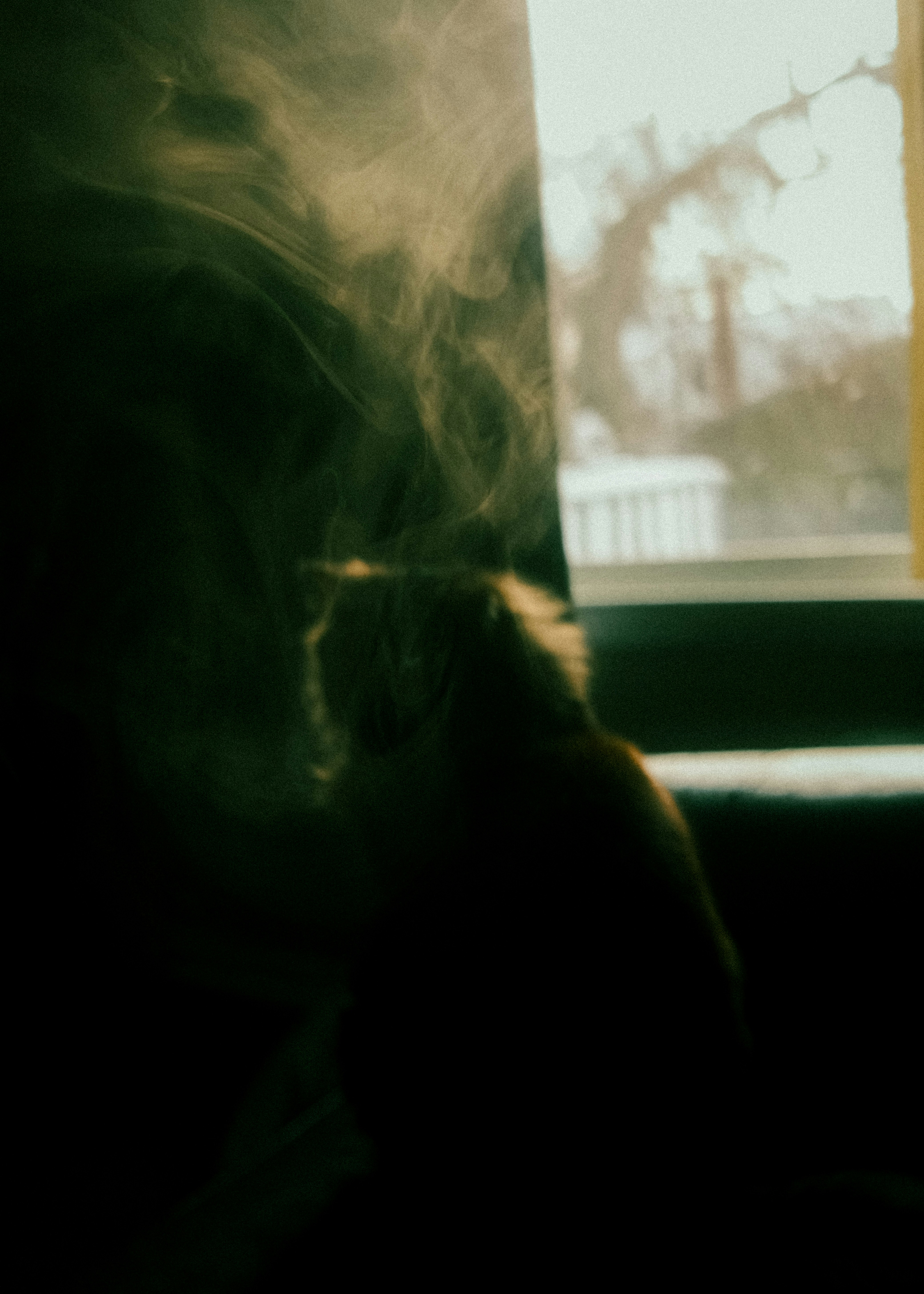 Soft backlight through a window frames a shadowed figure in a hazy room