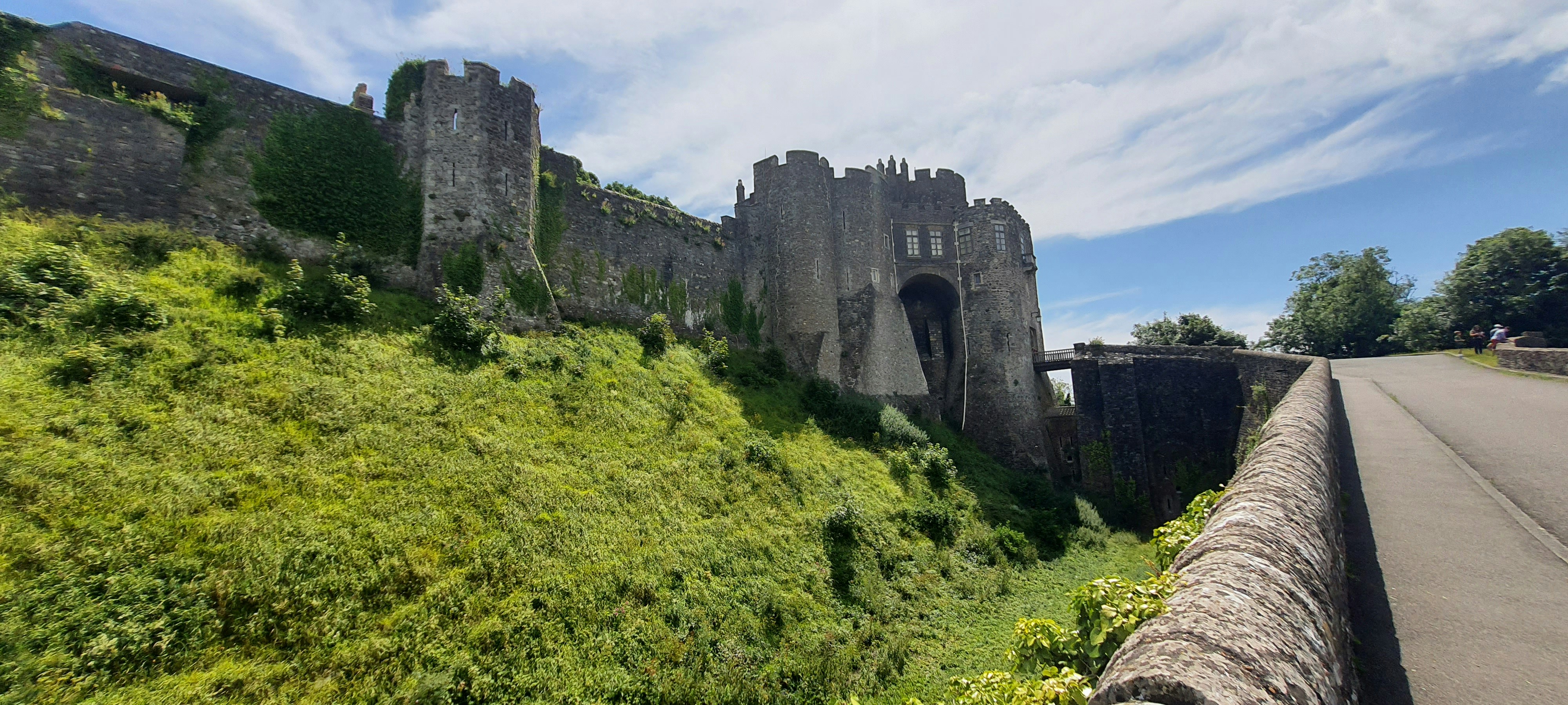 Ancient stone castle with a green grassy hillside.