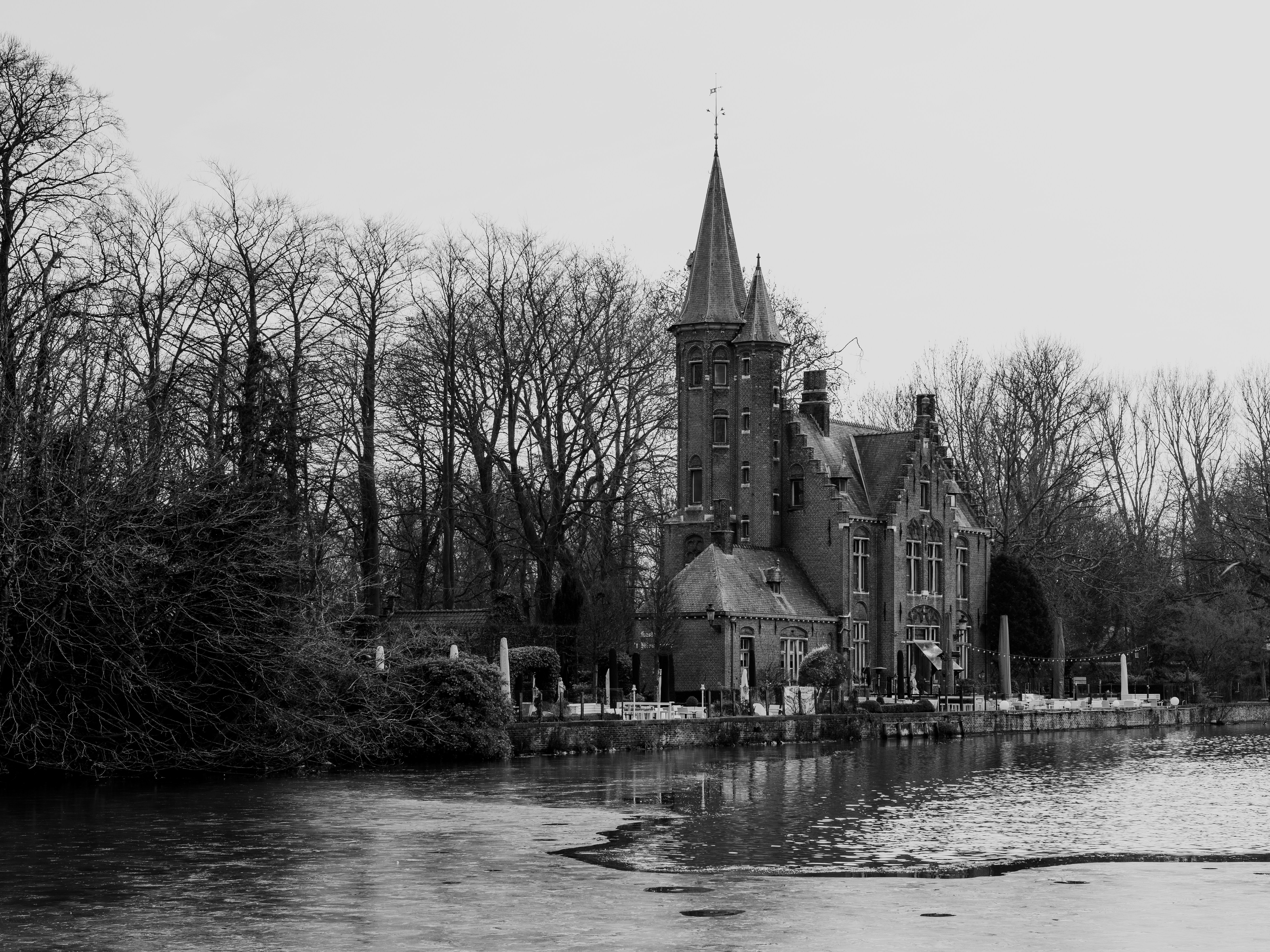 A gothic building by a lake with bare trees photo – Free Architecture ...