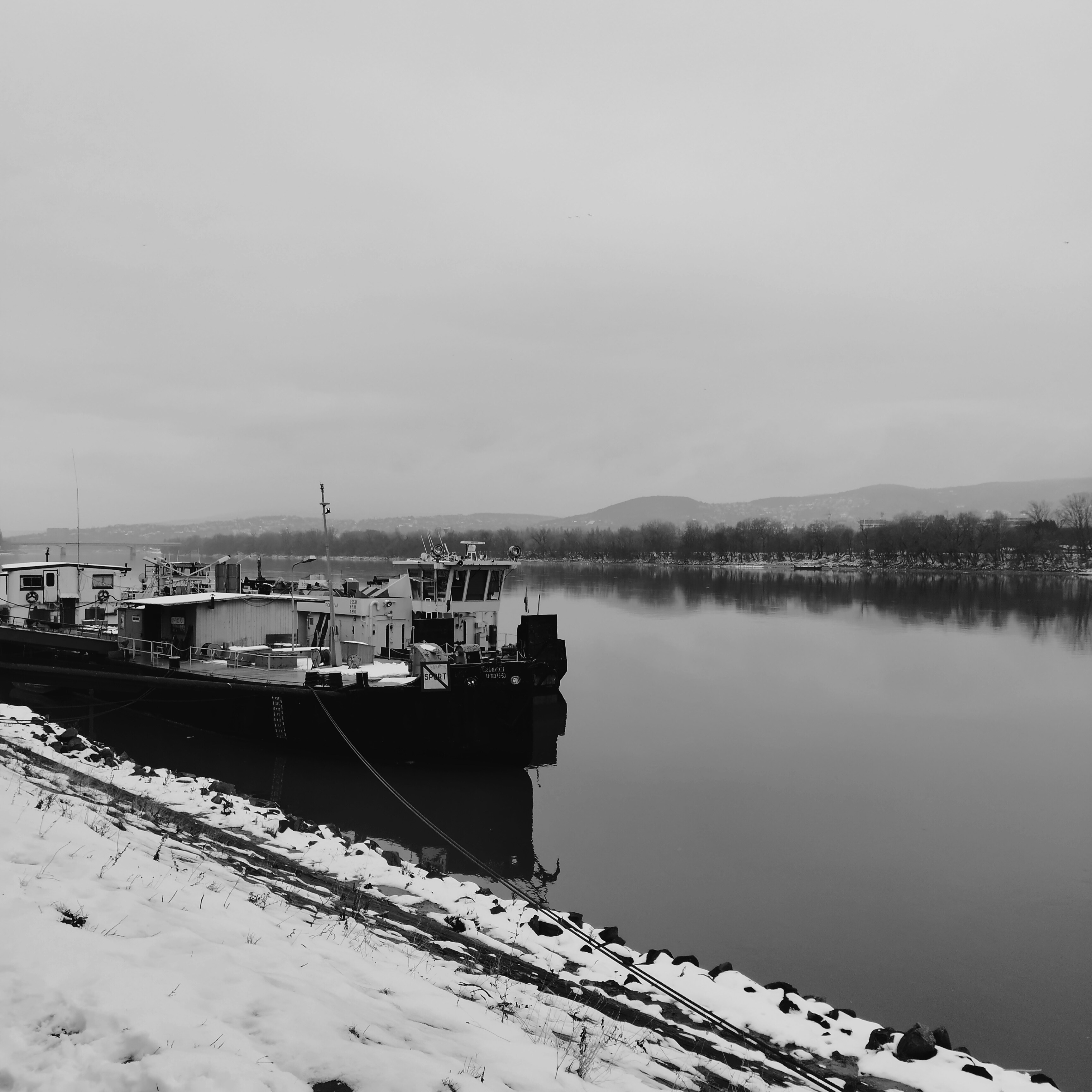 A barge floats on a calm river in winter.